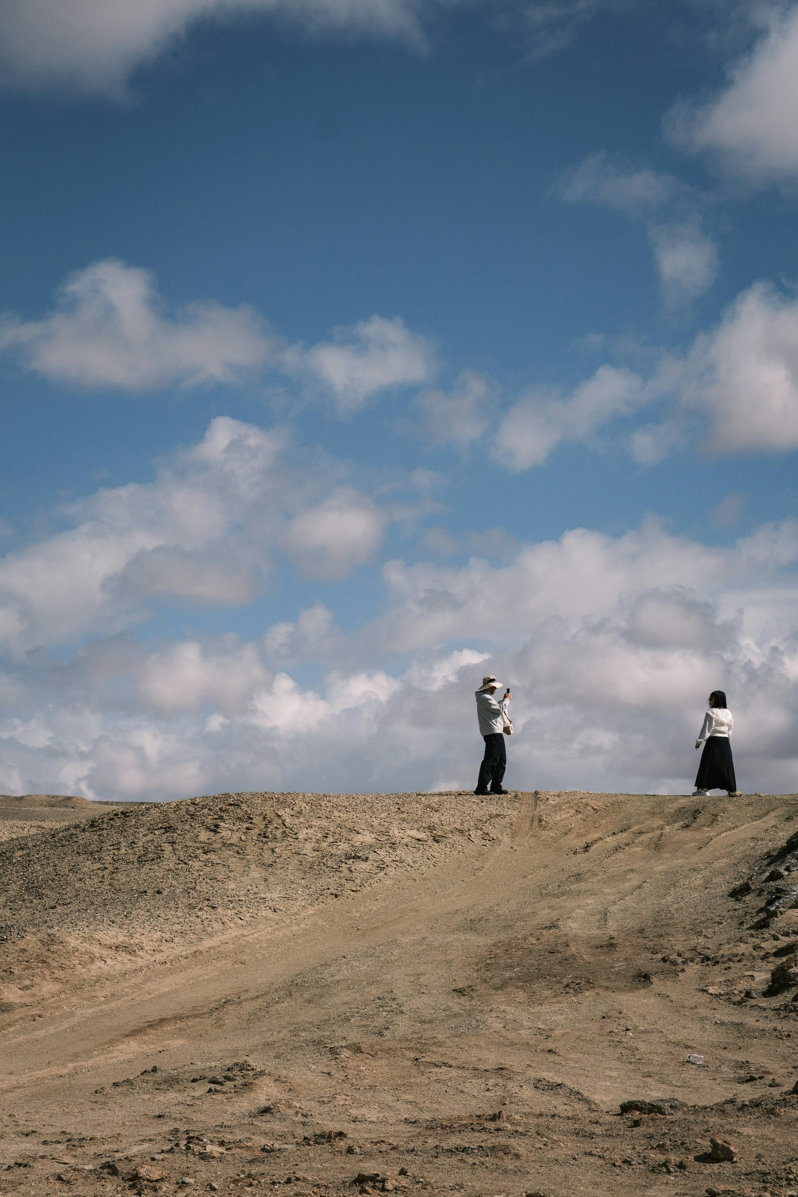 Silhouettes at the Horizon: Two Figures on a Dusty Ridge Under a Wide Sky