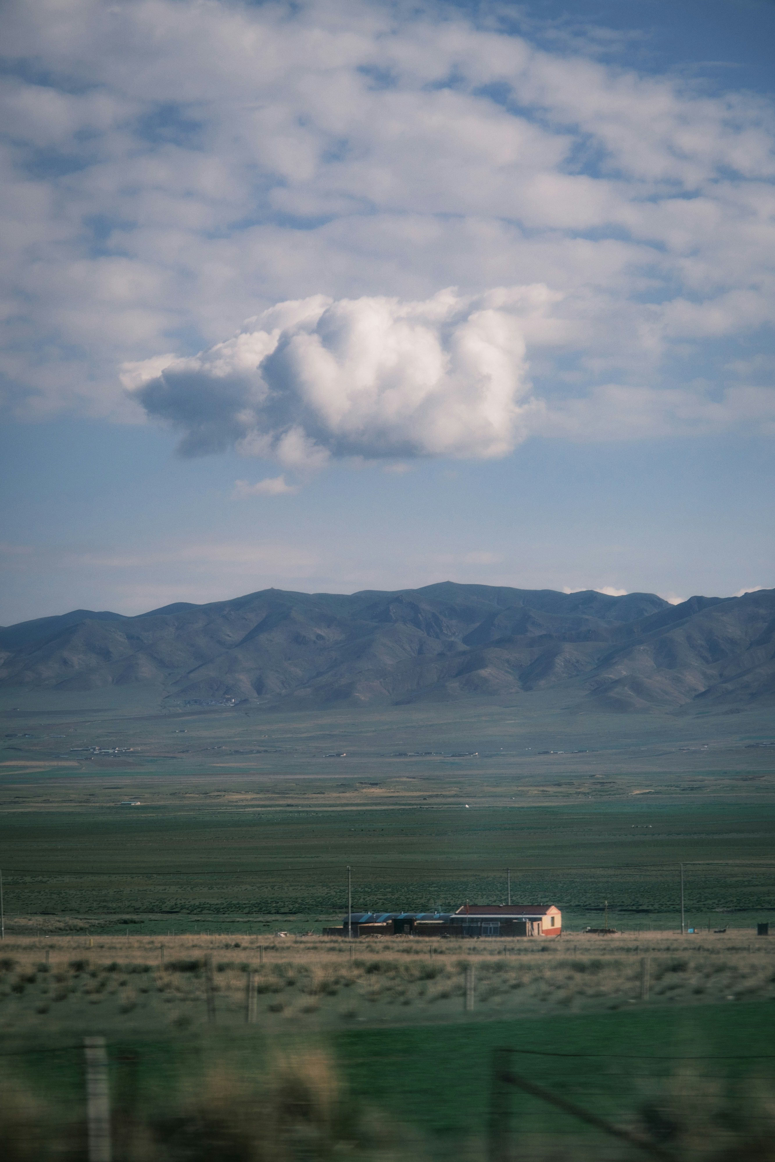 Quiet Valley Horizon with Lone Cabin Under a Plush Cloud