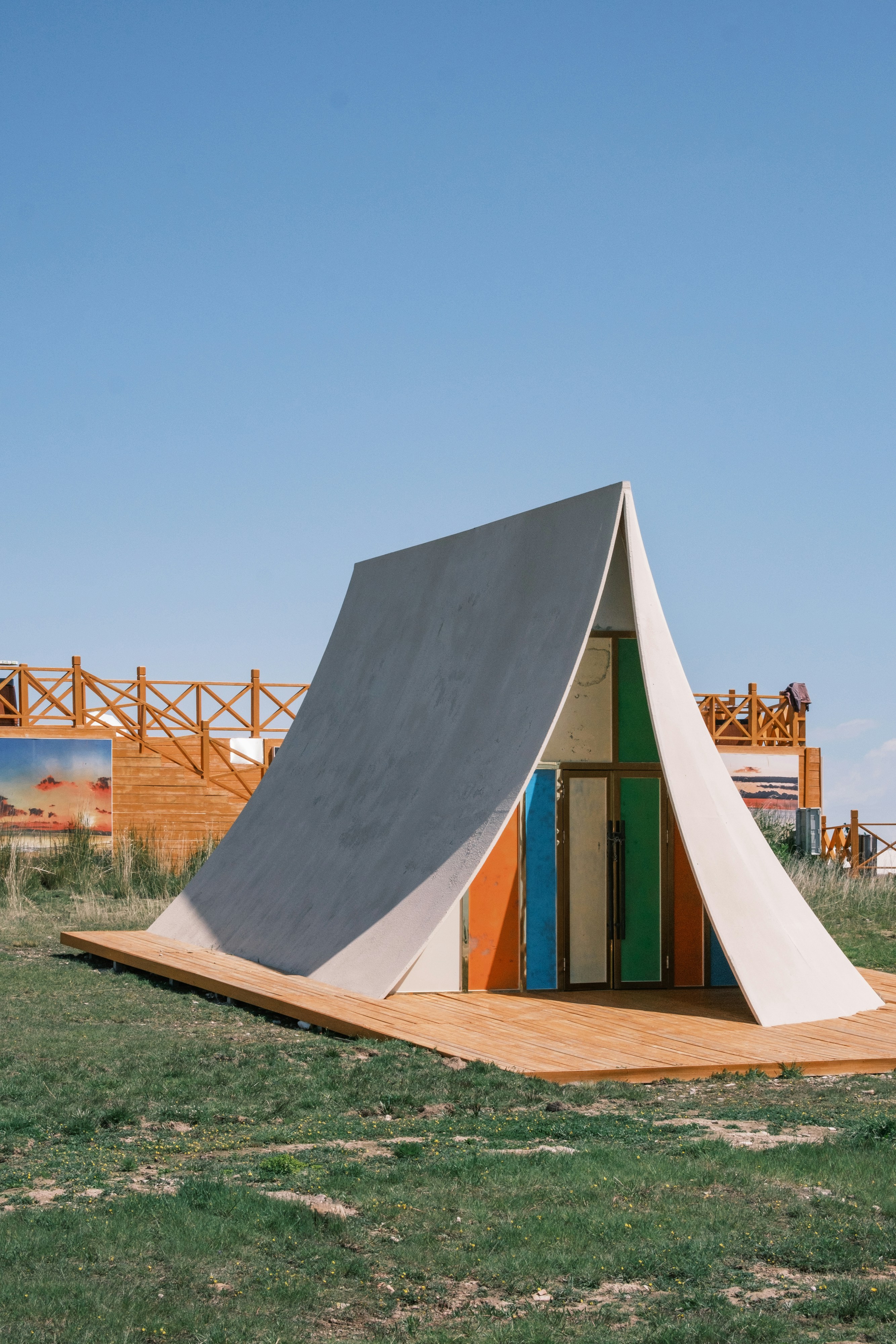 Canvas of Sunlit Shadows: A Curved Wing Unfolds Over a Colorful Entrance