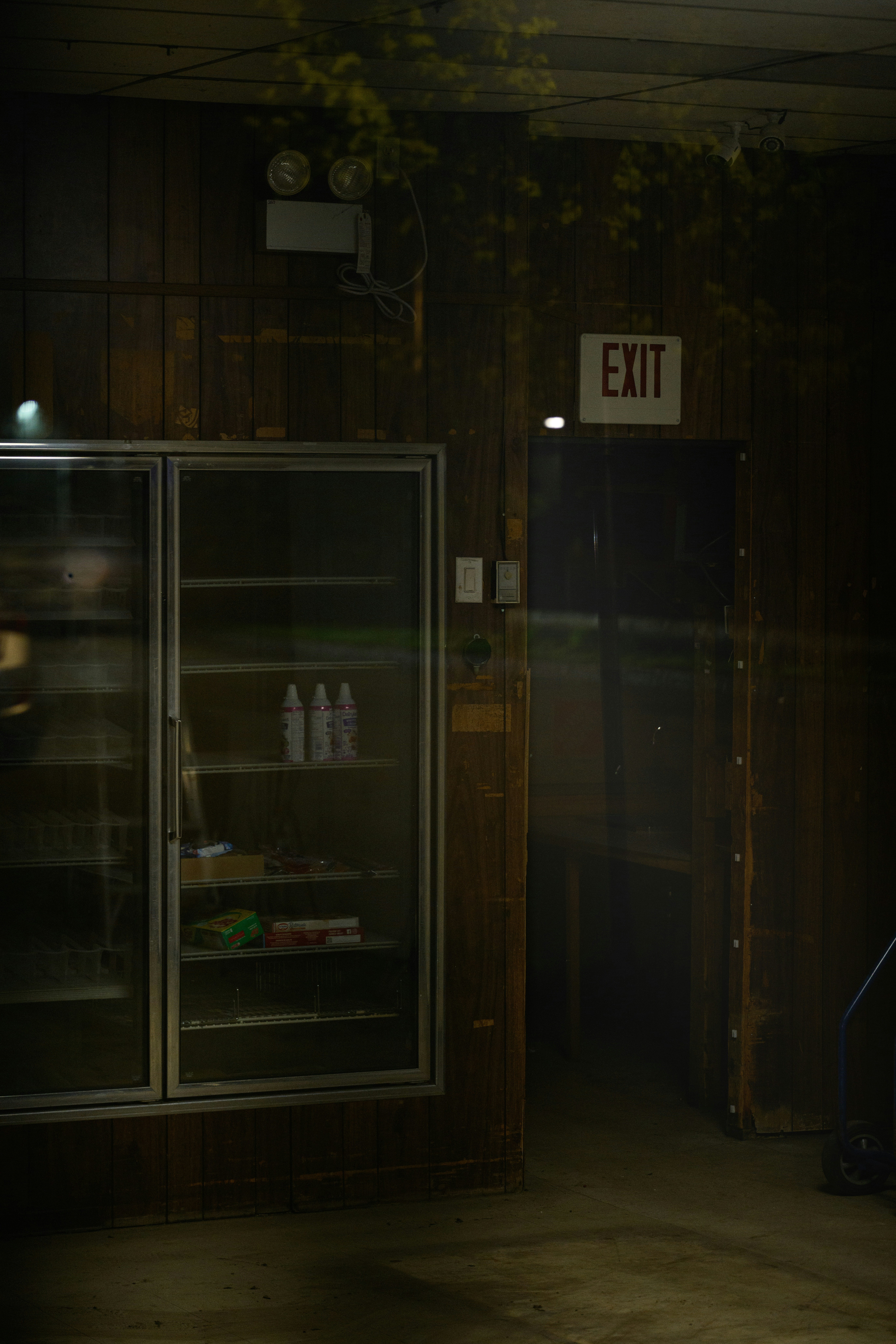 Dim Interior with Glass-Front Refrigerator and Exit Door