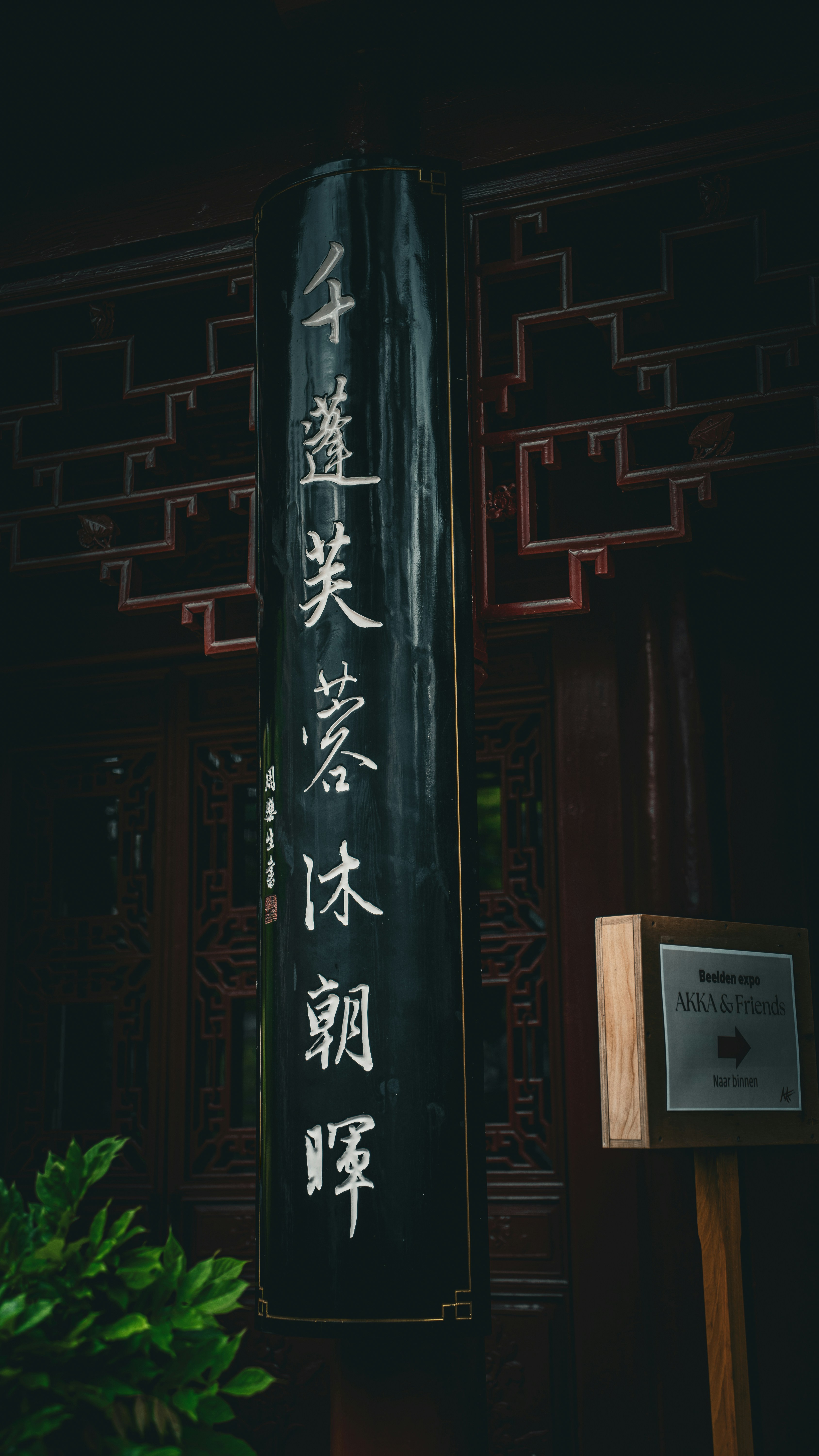 Vertical Inscription: A Dark Pillar Amidst Traditional Carved Panels