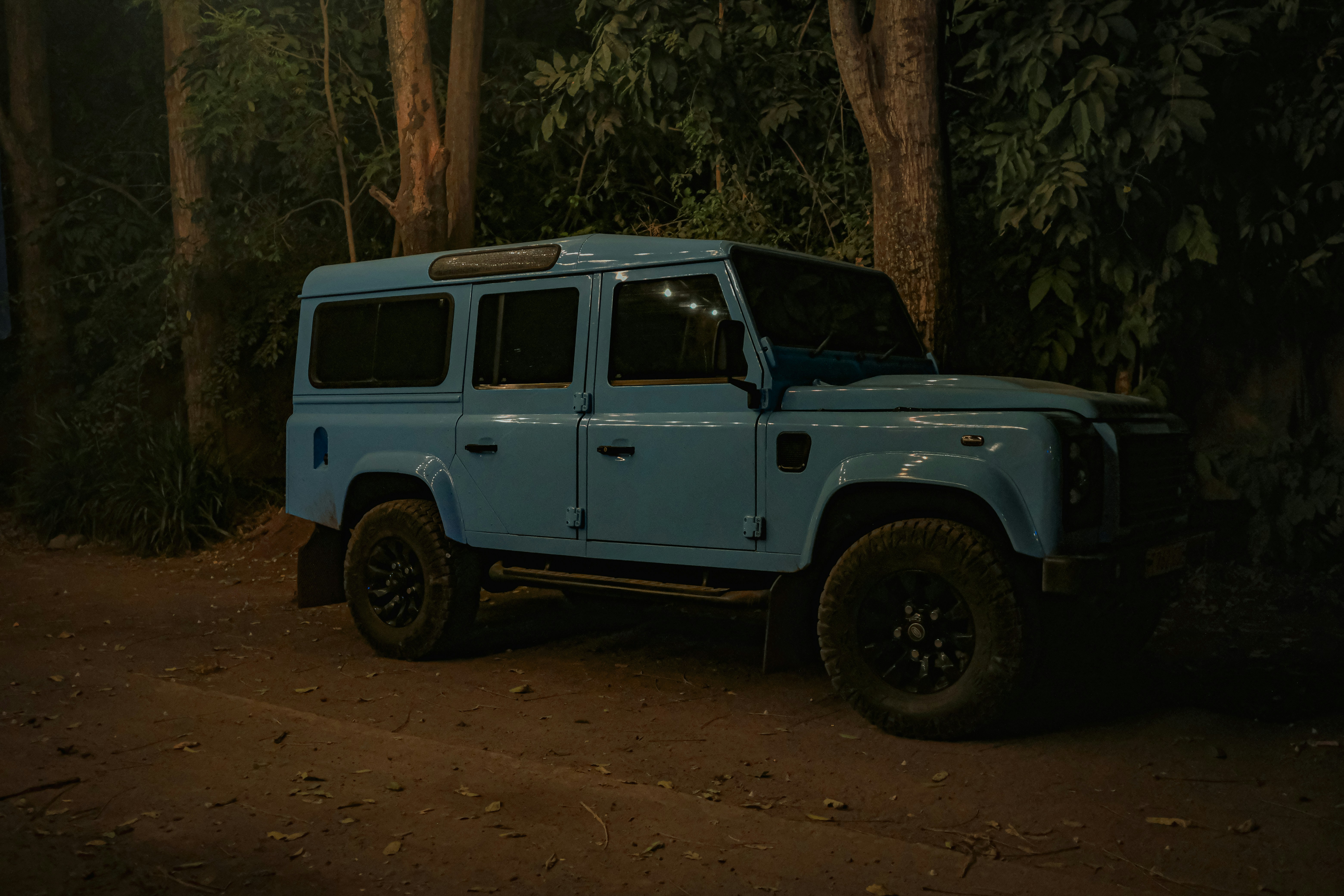 Blue Beast in Quiet Night: A Parked Defender Under Dim Canopy