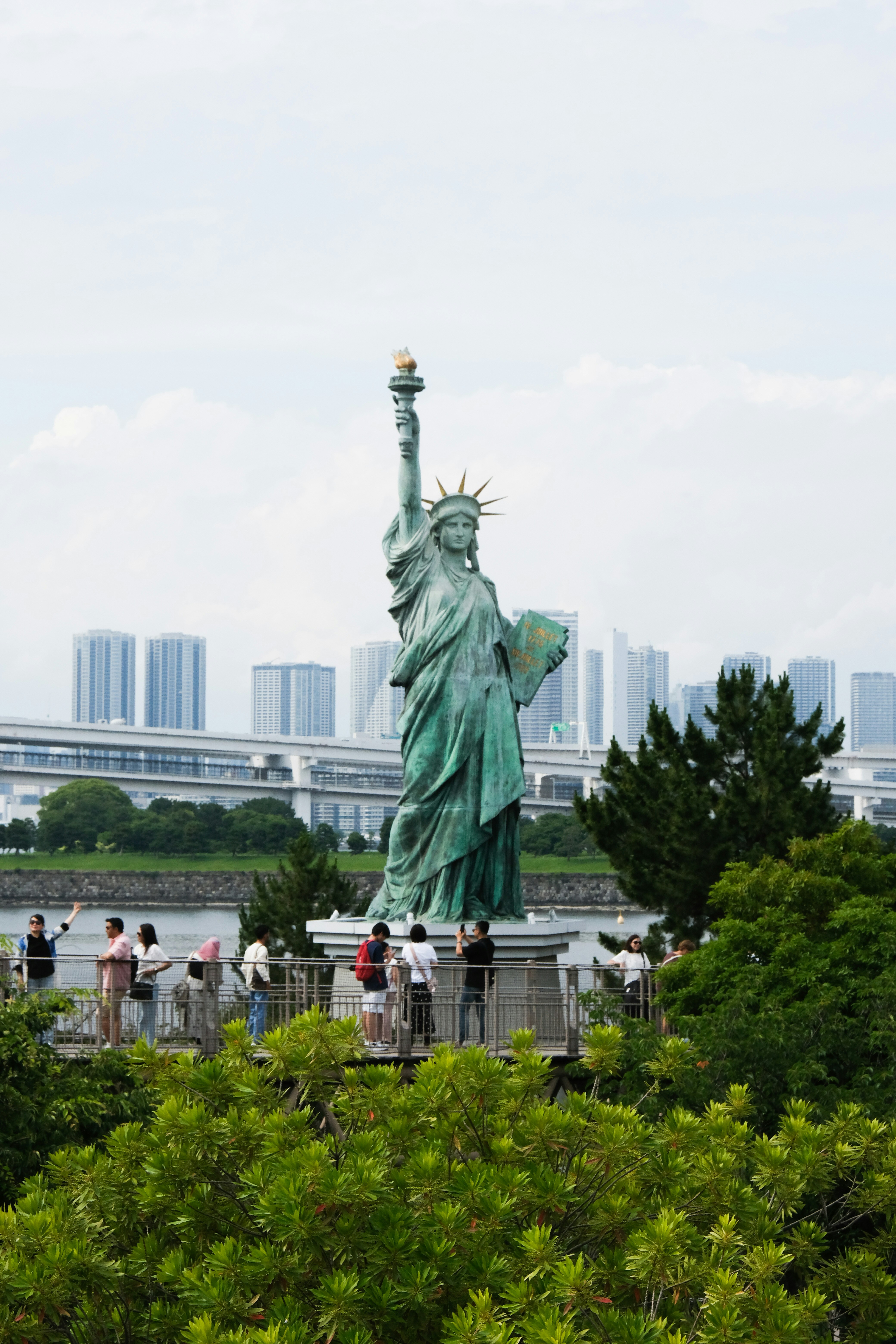 Statue of Liberty Overlooking a Cityscape Across a River Park