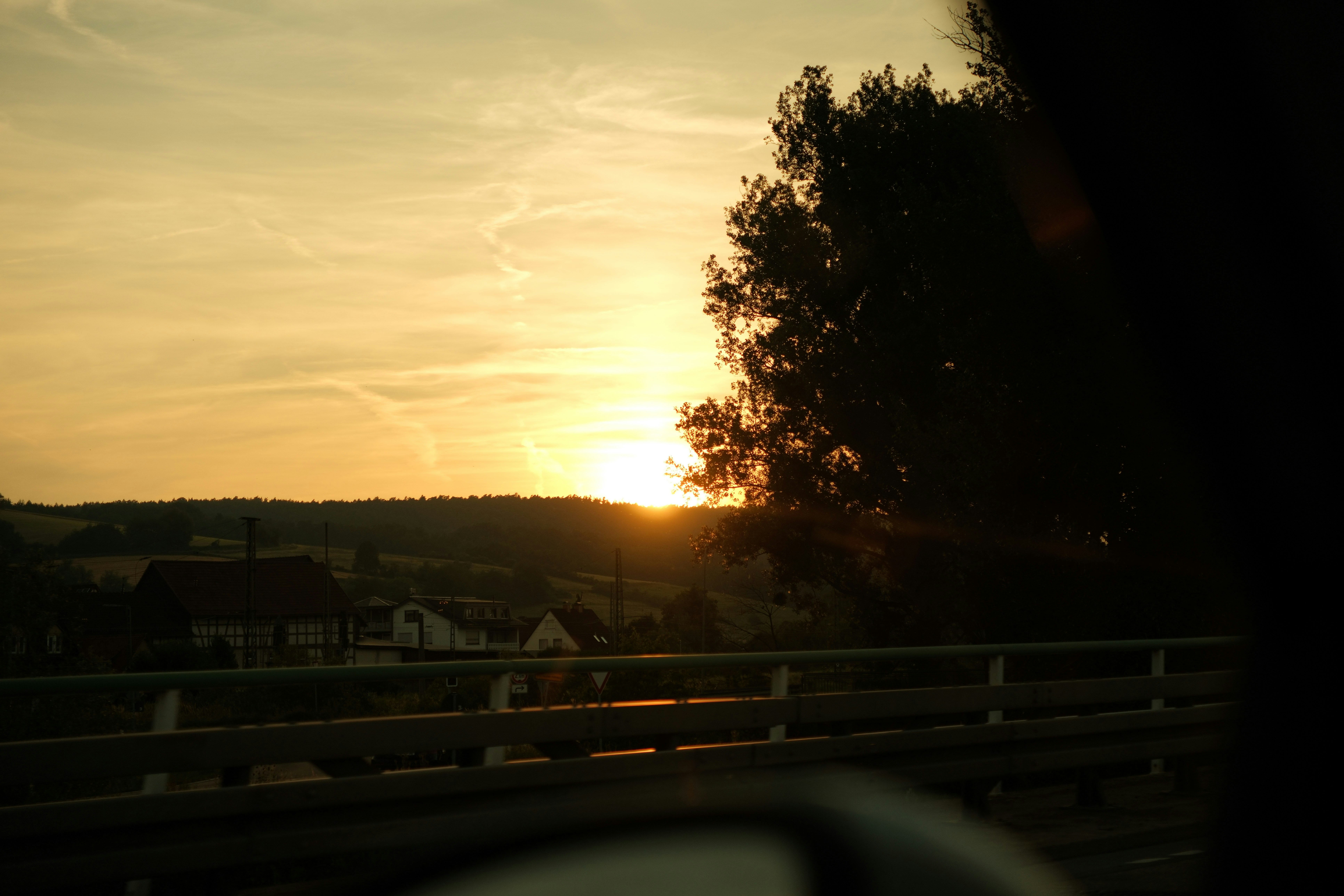 Sunset over a distant town framed by a car window silhouette