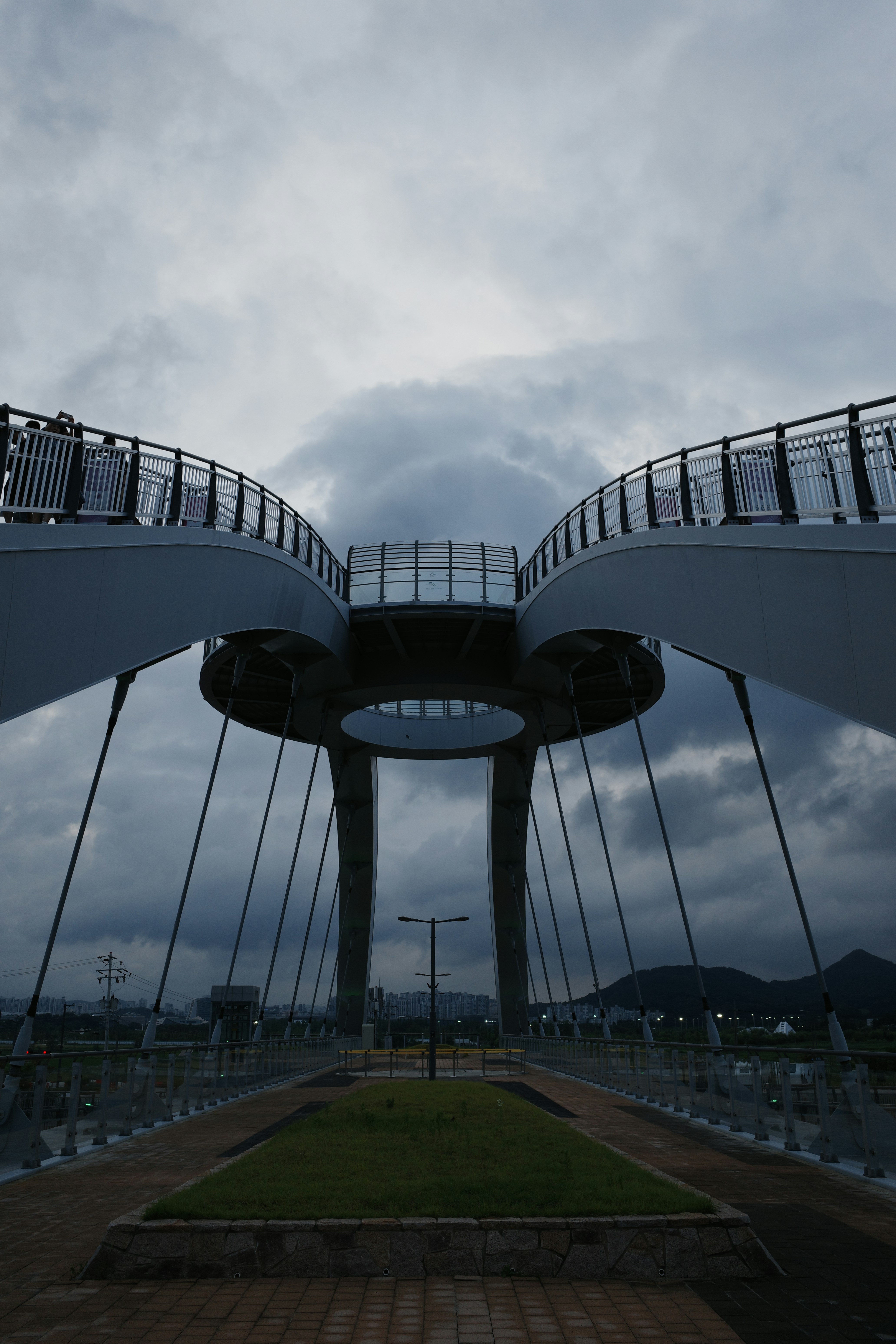 Suspended Gateway: a central arch frames the approach to a quiet park