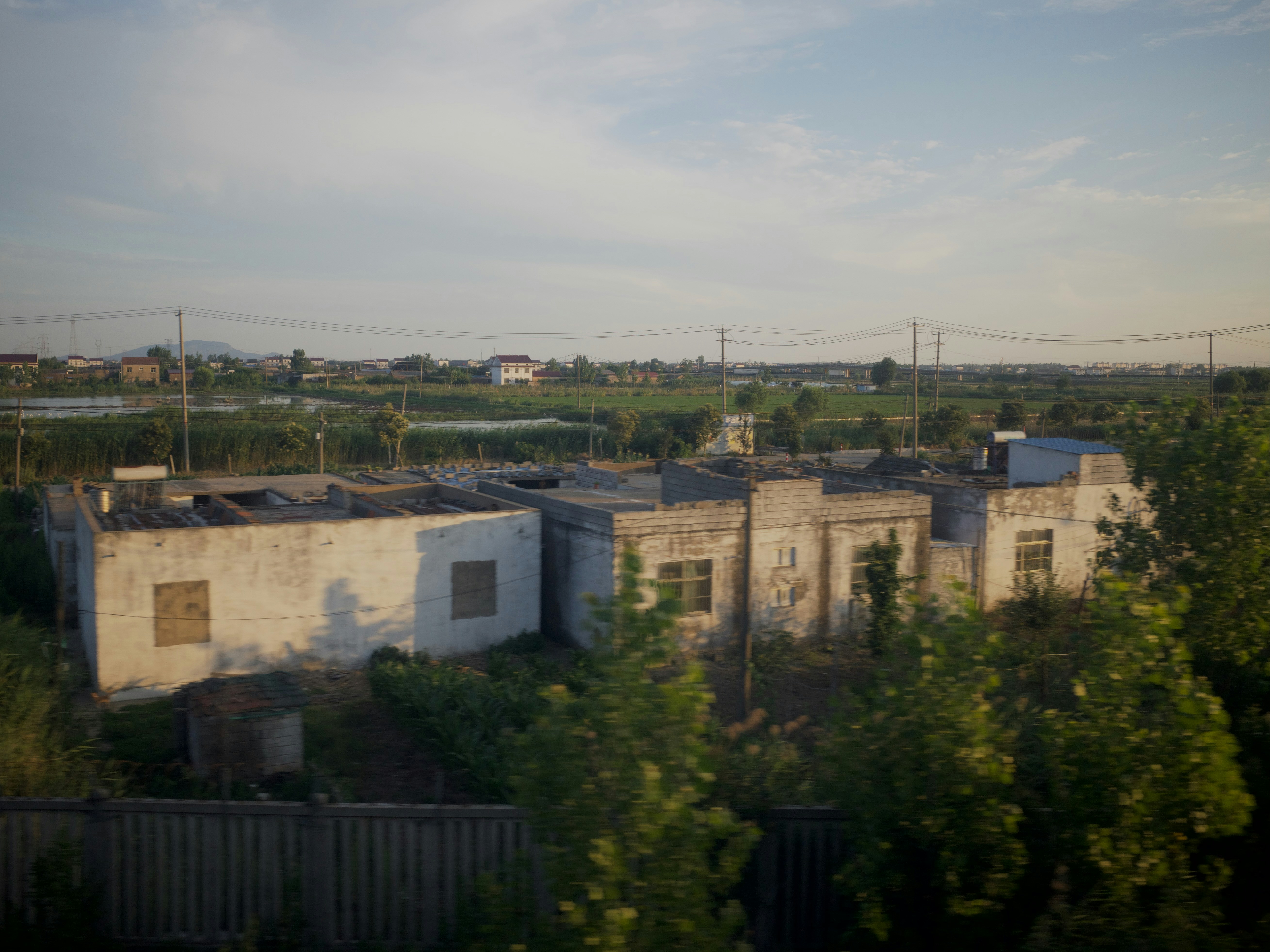 Sunlit Row of Crumbling Bungalows Beneath a Wide Sky