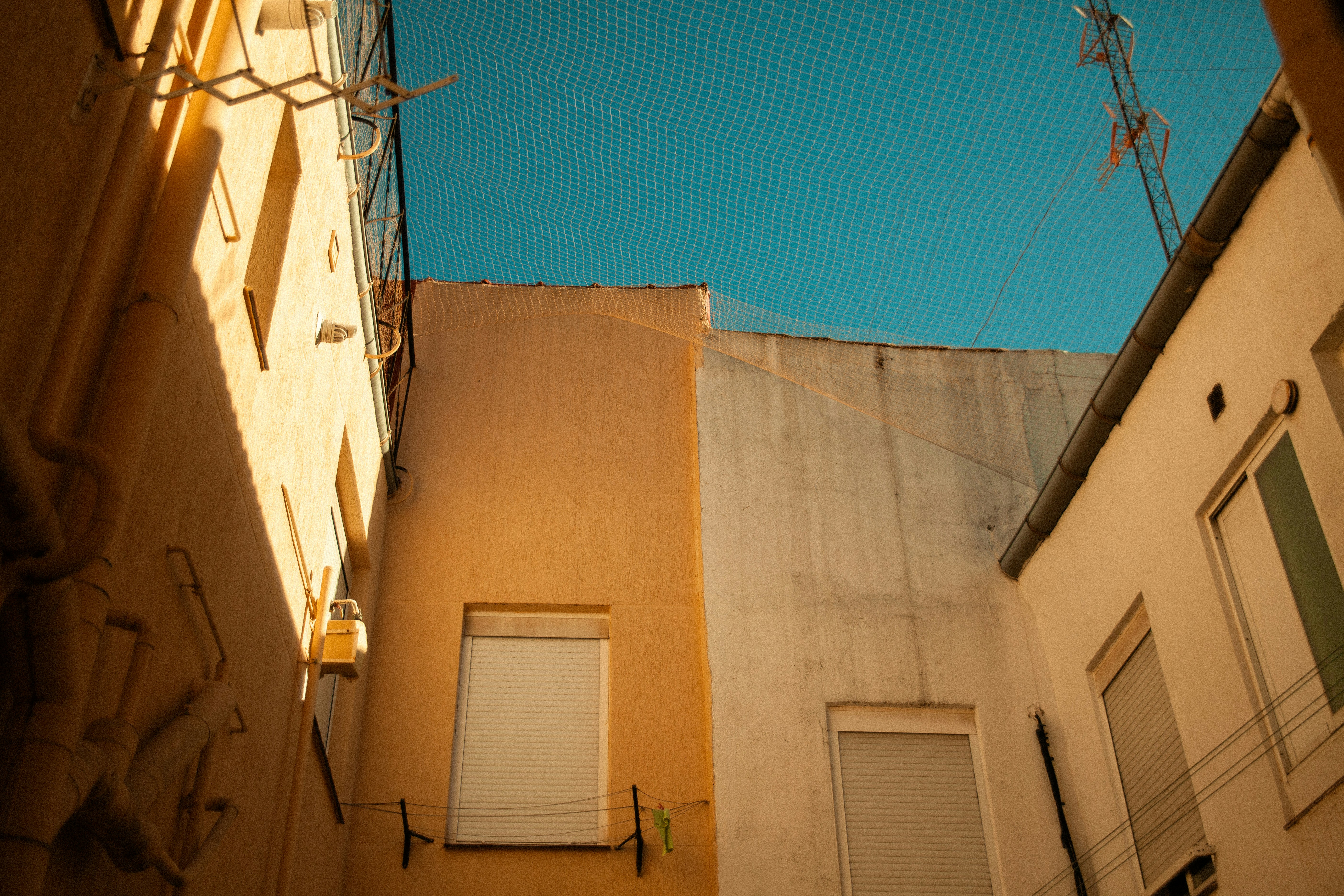 Sunlit Alleyway: Warm Facade Contrast under Blue Sky