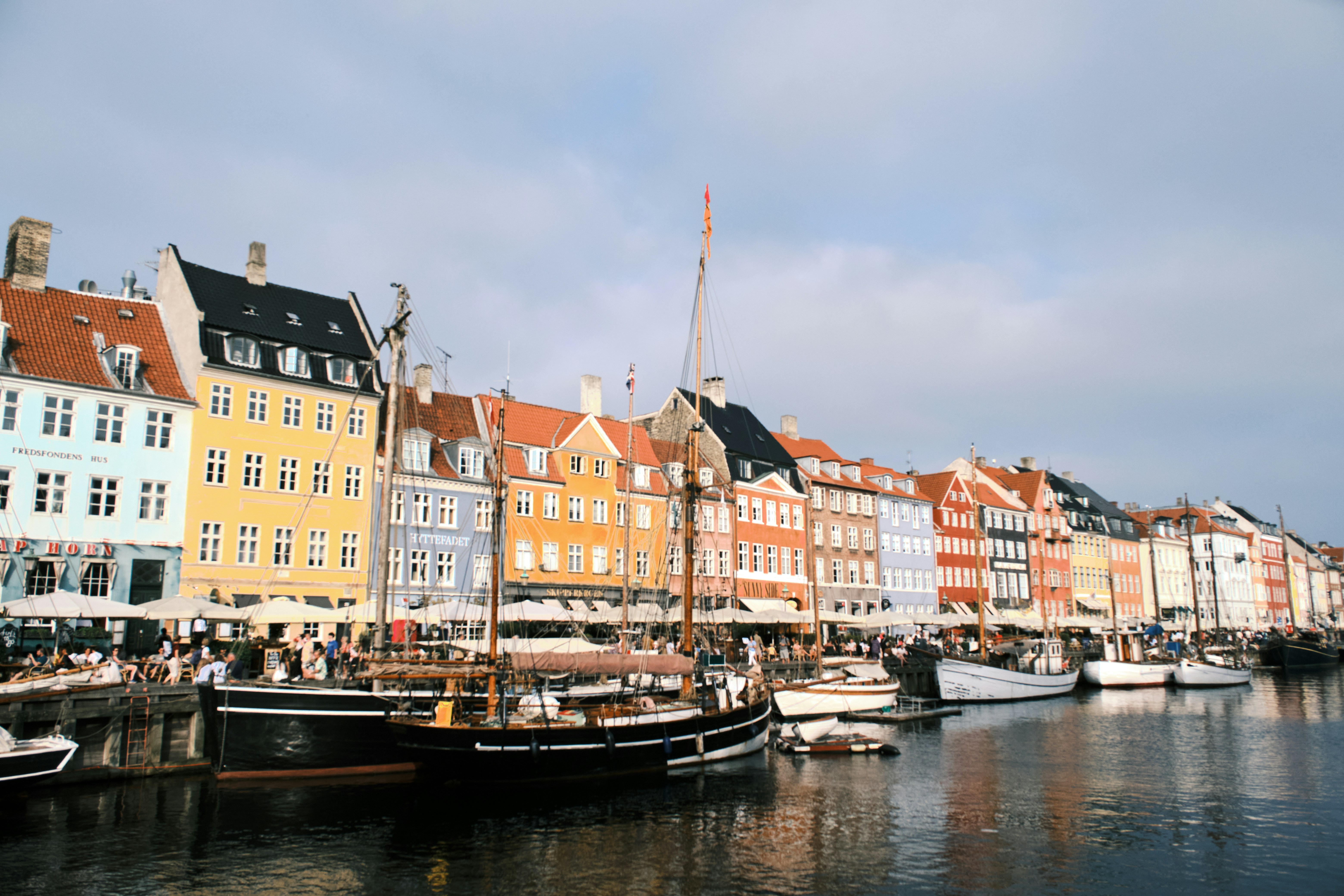Colorful waterfront row: stacked houses and sailboats along a Nordic harbor