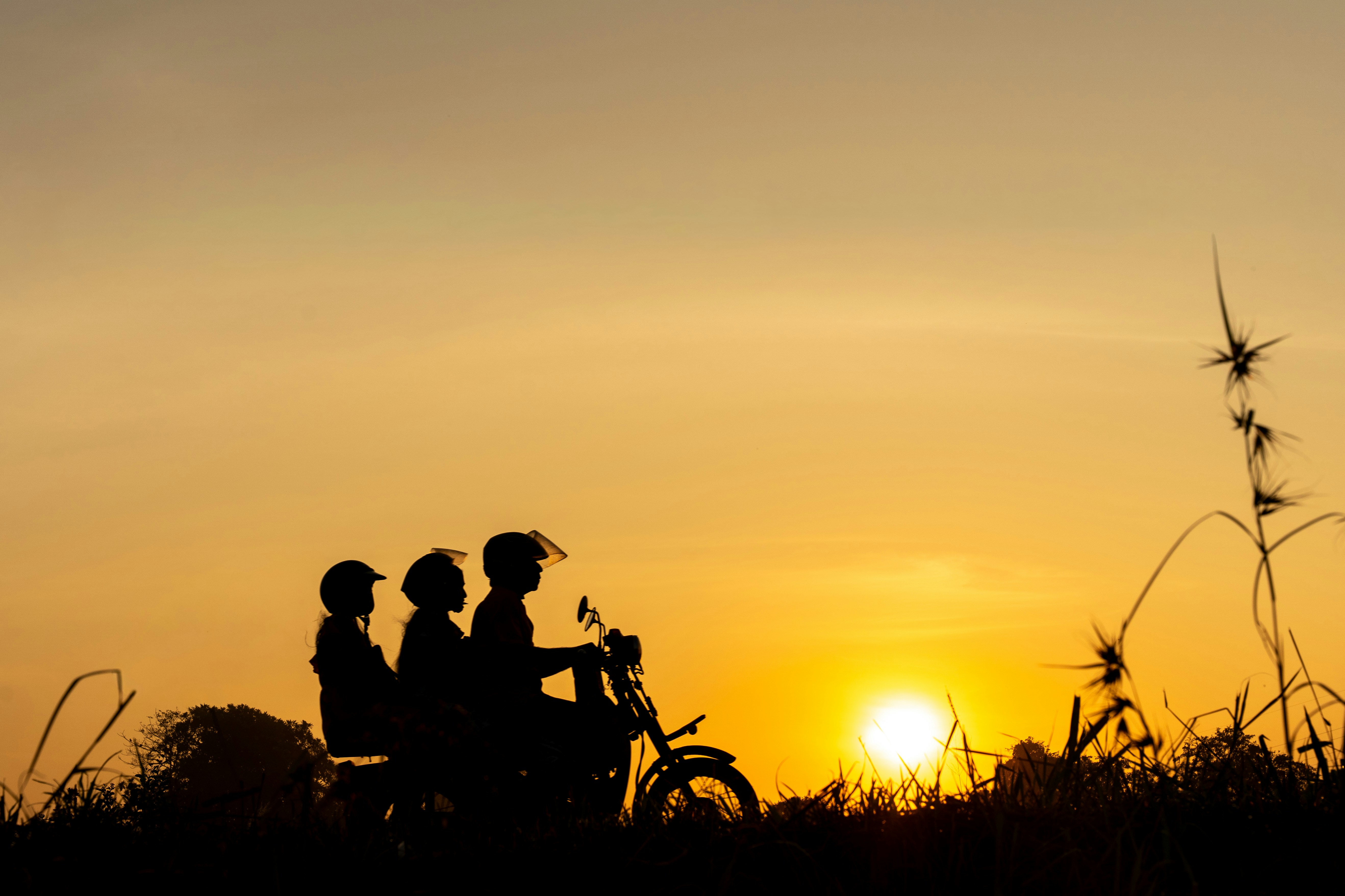 Sunlit silhouettes: a trio on a hill with a motorcycle at dusk