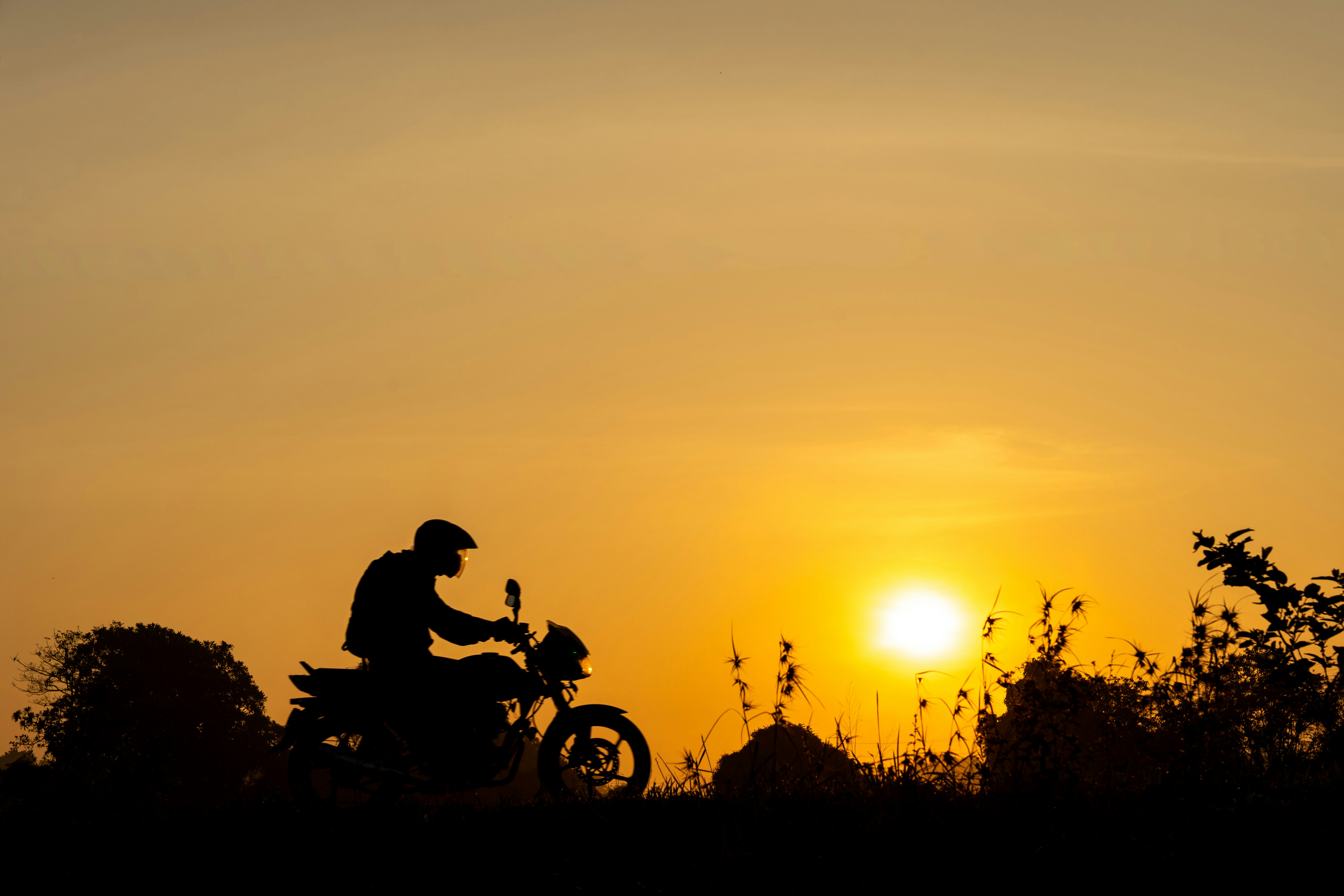 Silhouette at Sunset: Rider and Bike Against a Sunlit Horizon