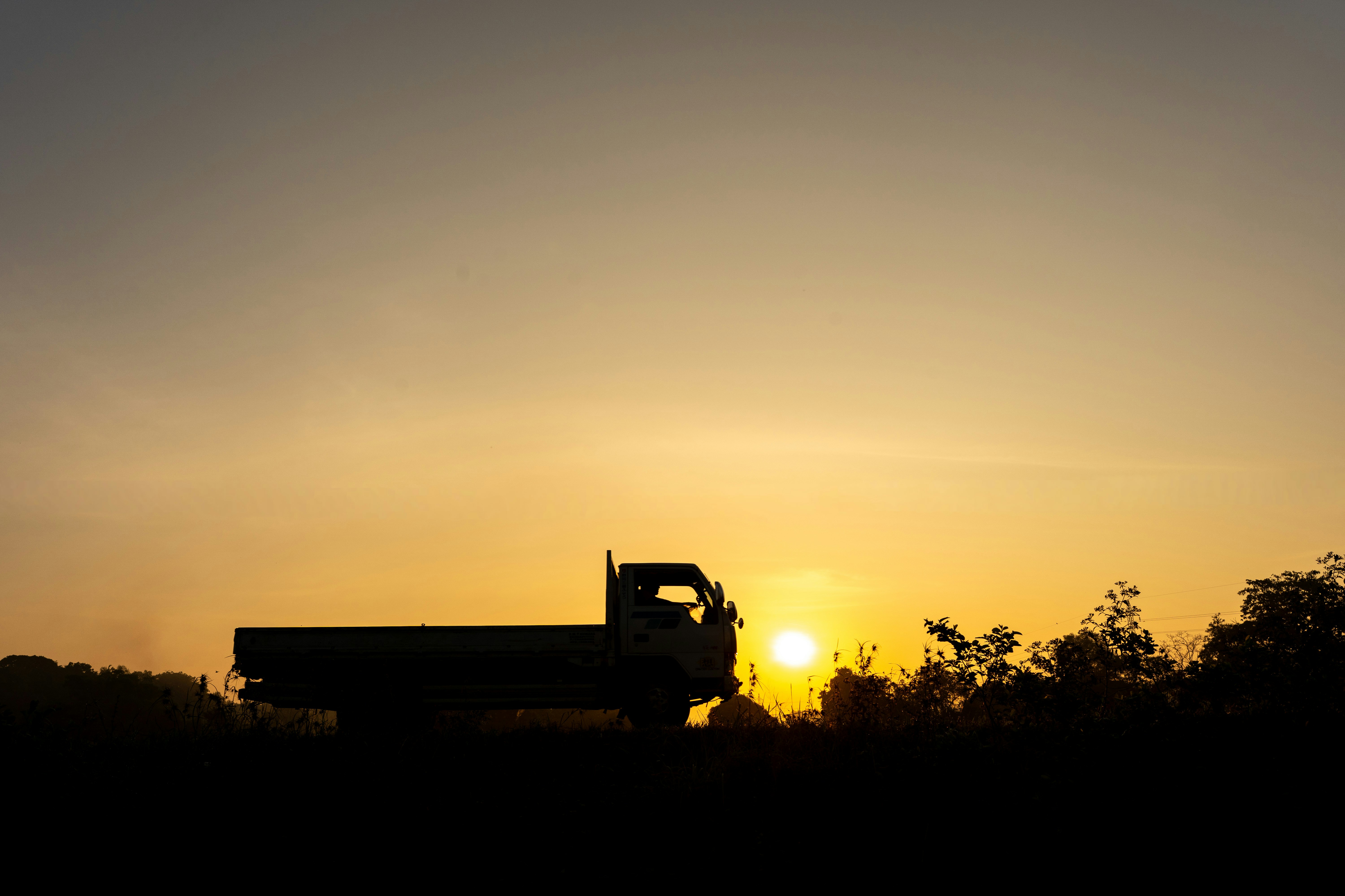 Sunlit Silhouette: A Truck at Dusk on a Quiet Horizon