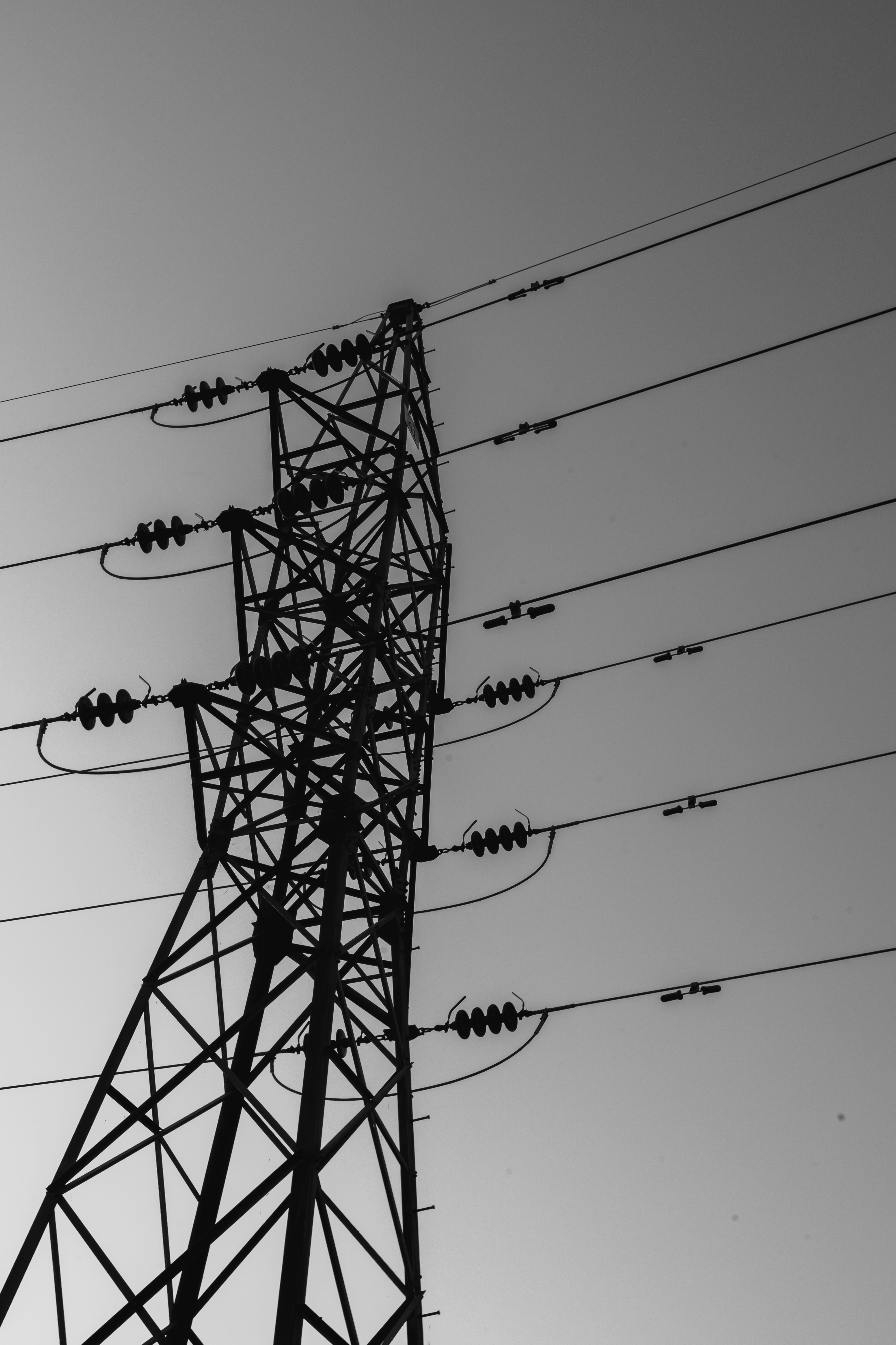Monumental Lattice: A towering power line pylon against a minimalist sky