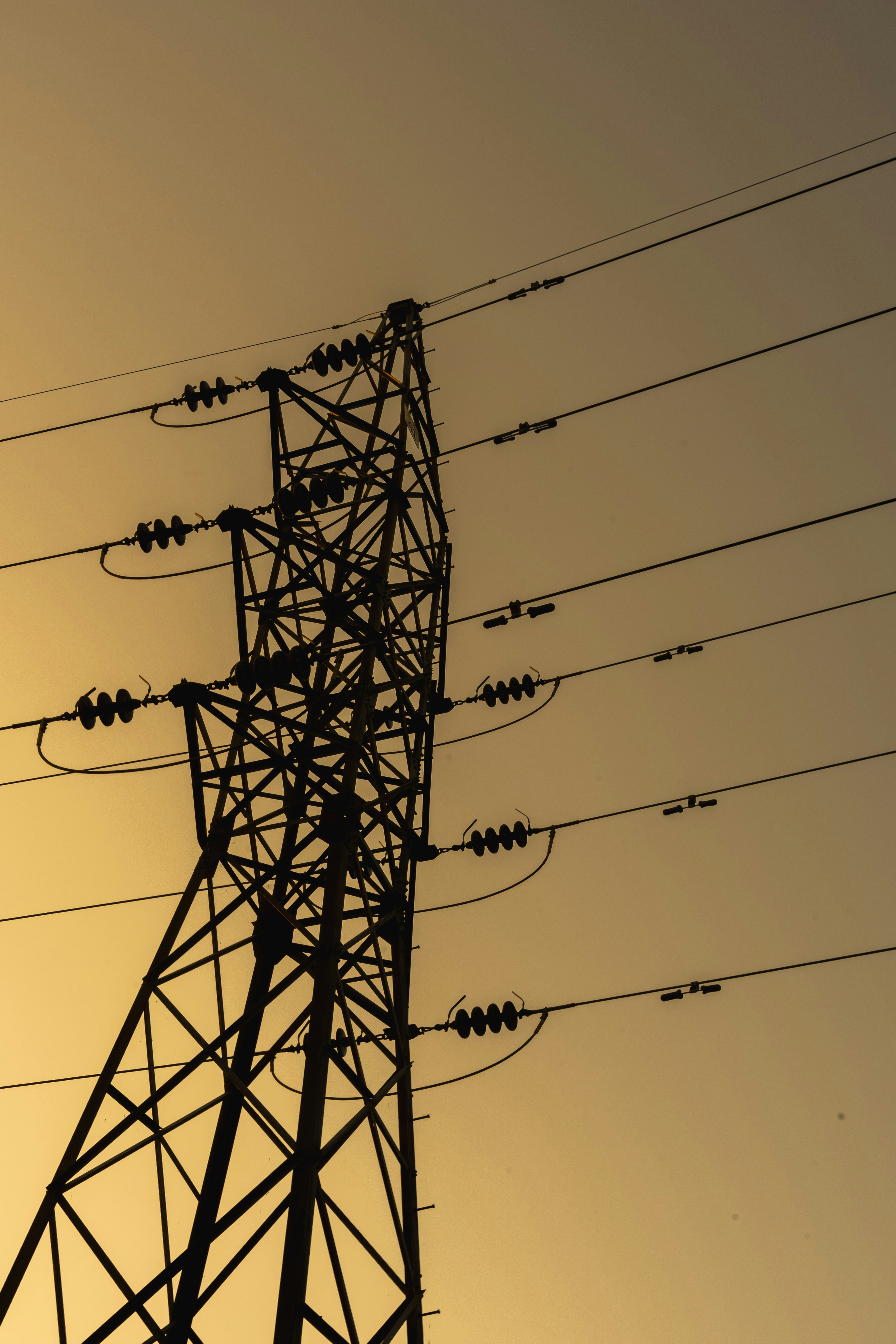 Silhouette of a Transmission Tower Against a Golden Dusk Sky