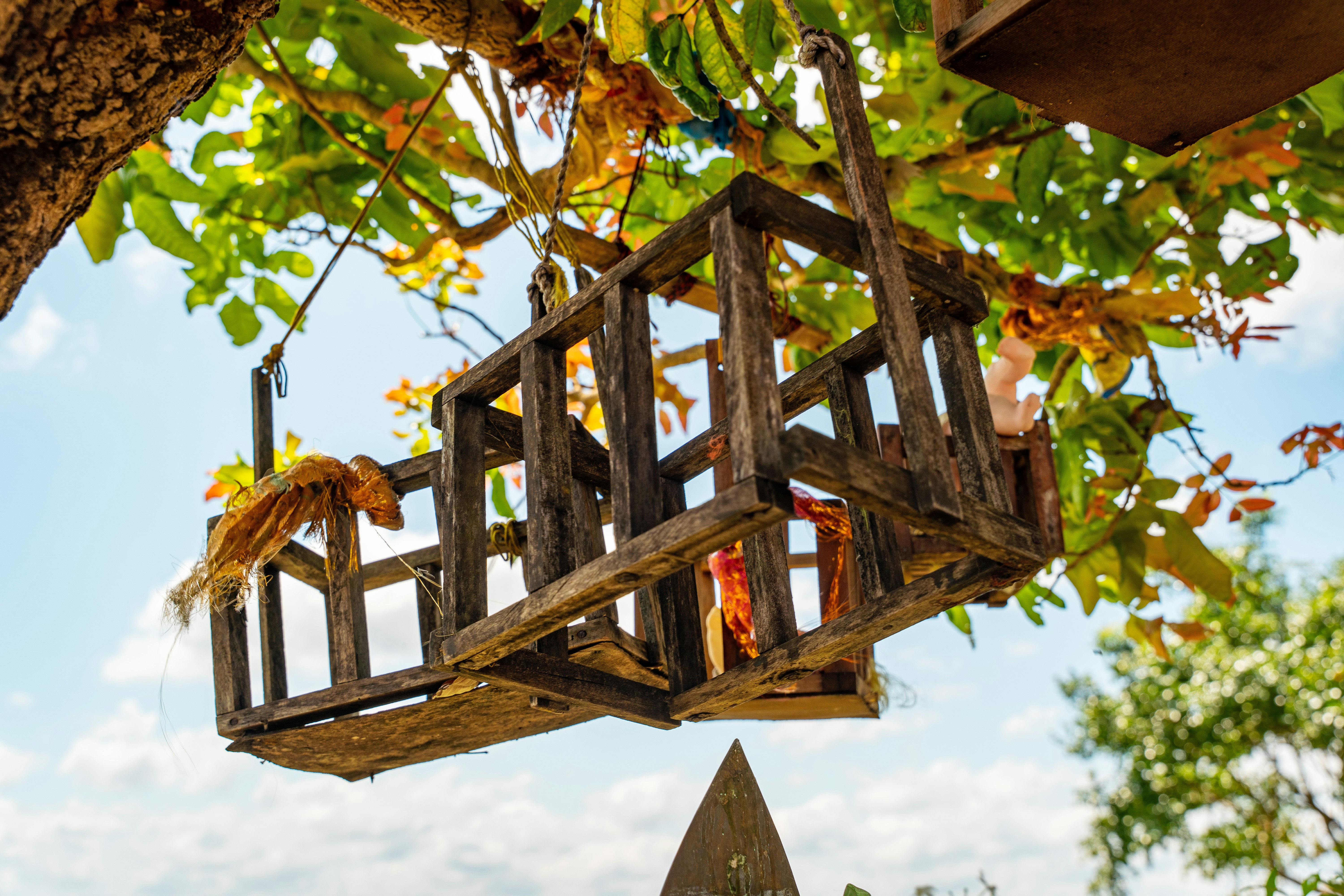 Wooden Hanging Cage Against a Bright Sky in a Garden