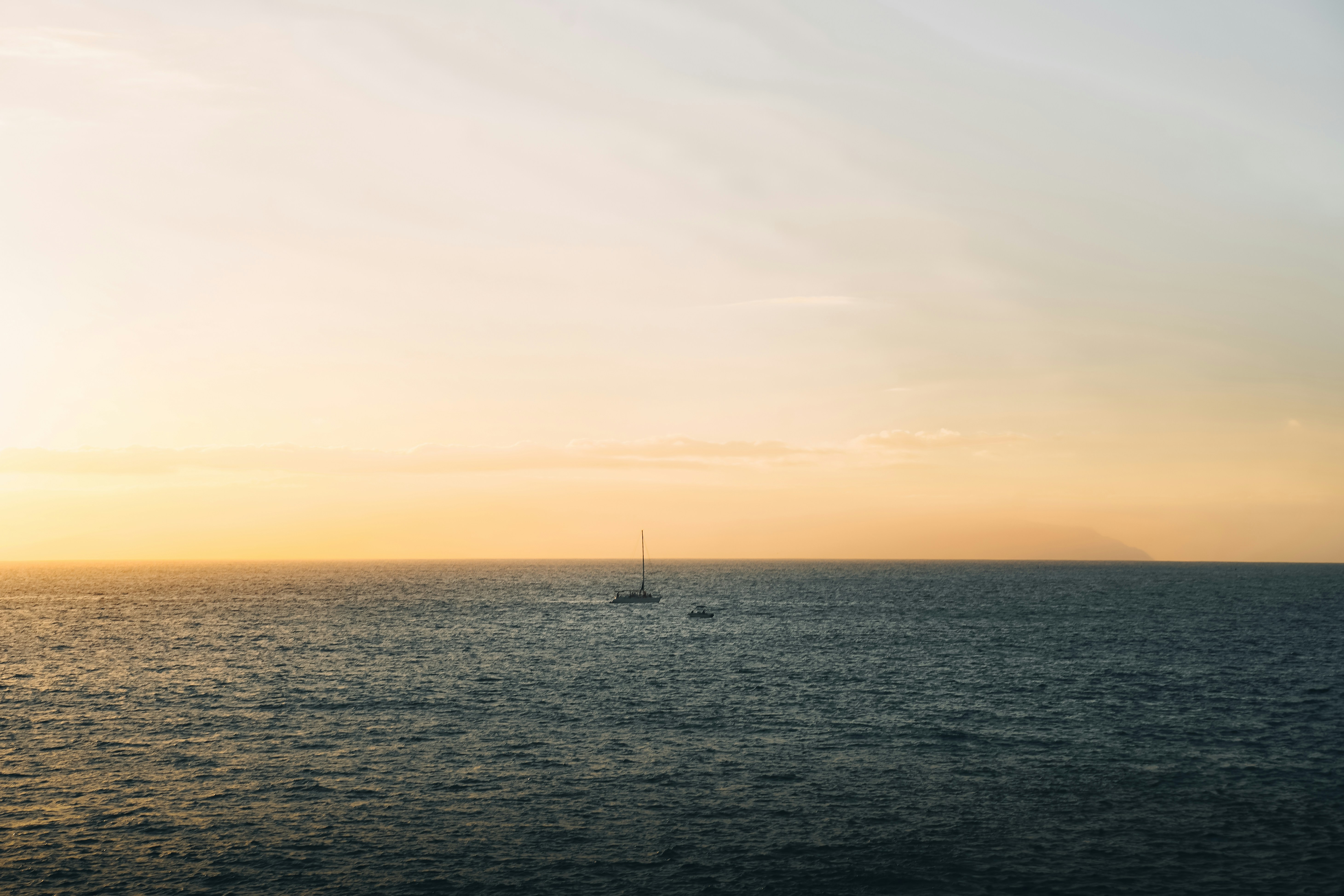Serene Horizon: A Lone Sailboat at Dusk