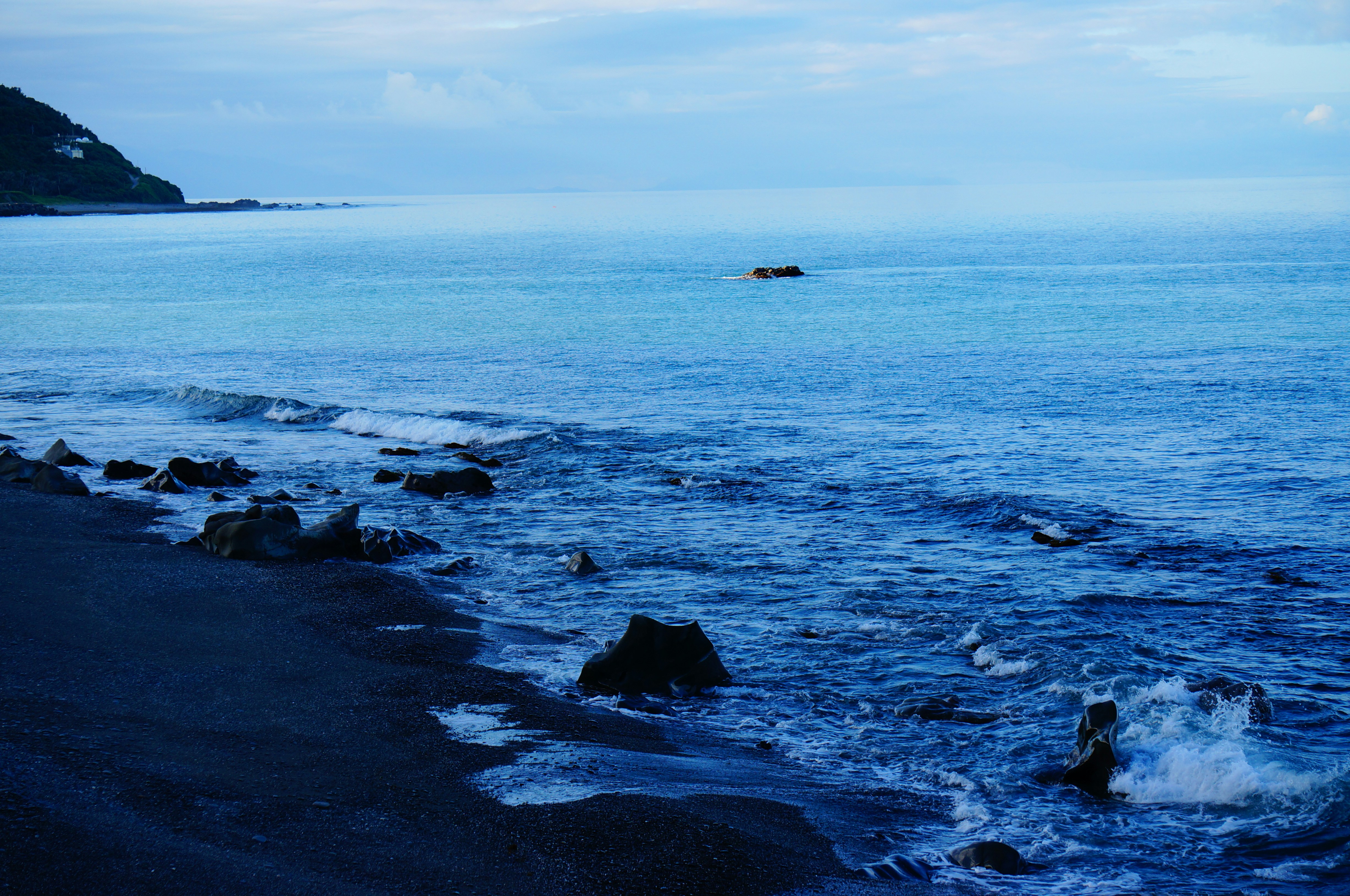 Blue Horizon at Dawn: Quiet Sea along a Rocky Shore