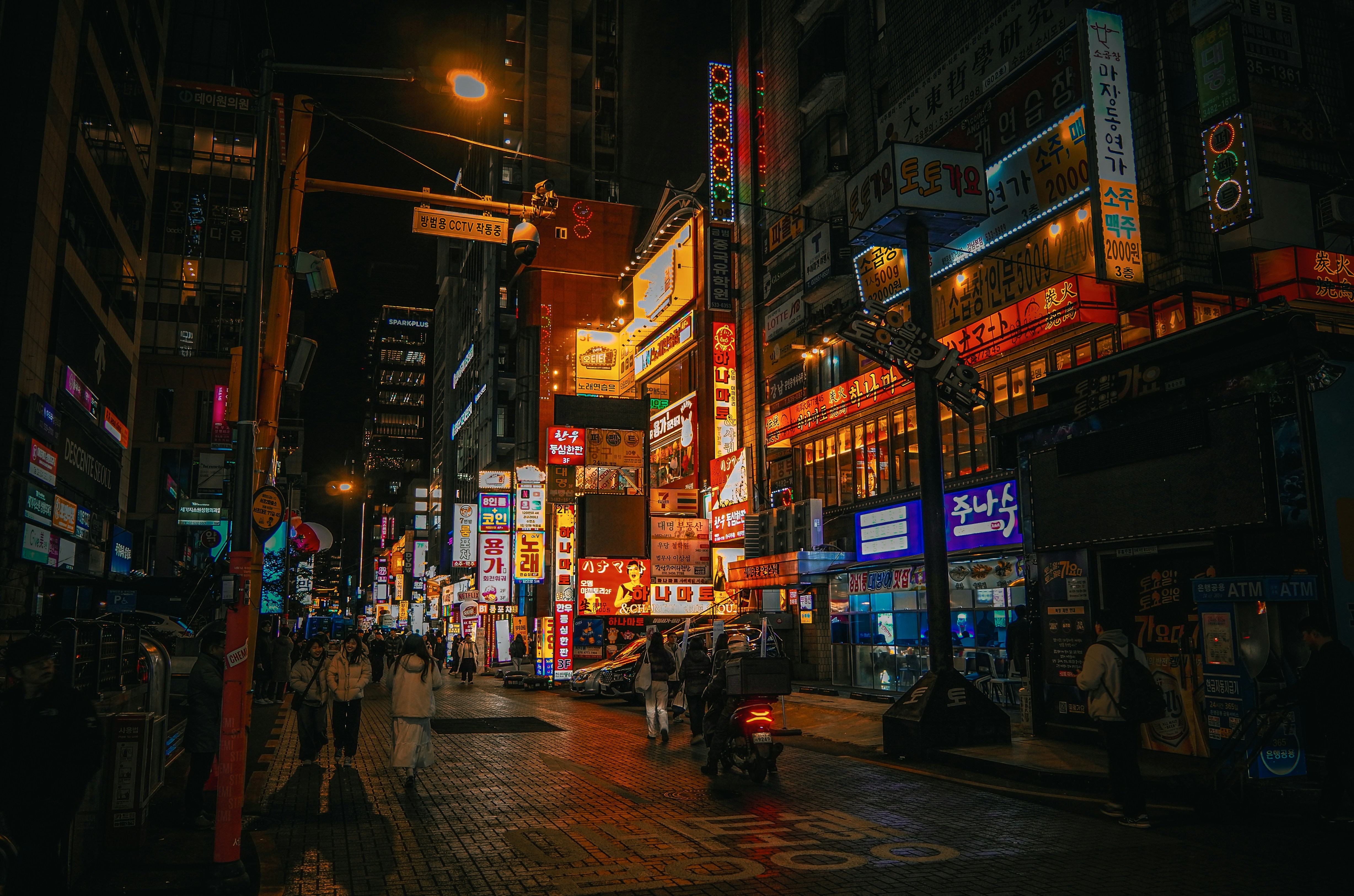 Vibrant city street at night with neon signs and pedestrians; a moody urban scene highlighting nightlife energy and architectural signage.