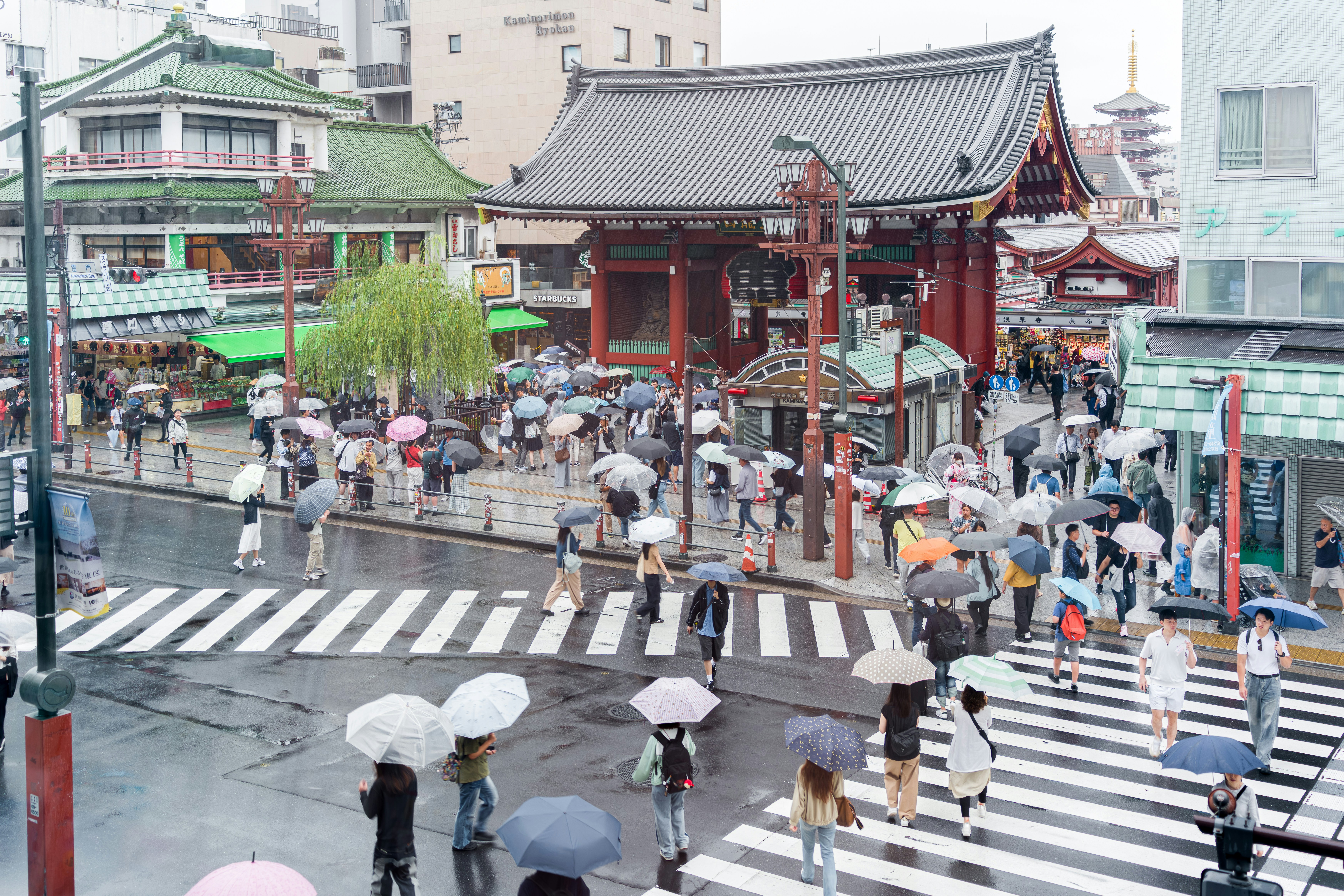 Rainy Crossing: People with Umbrellas Traverse a Traditional Japanese Gate