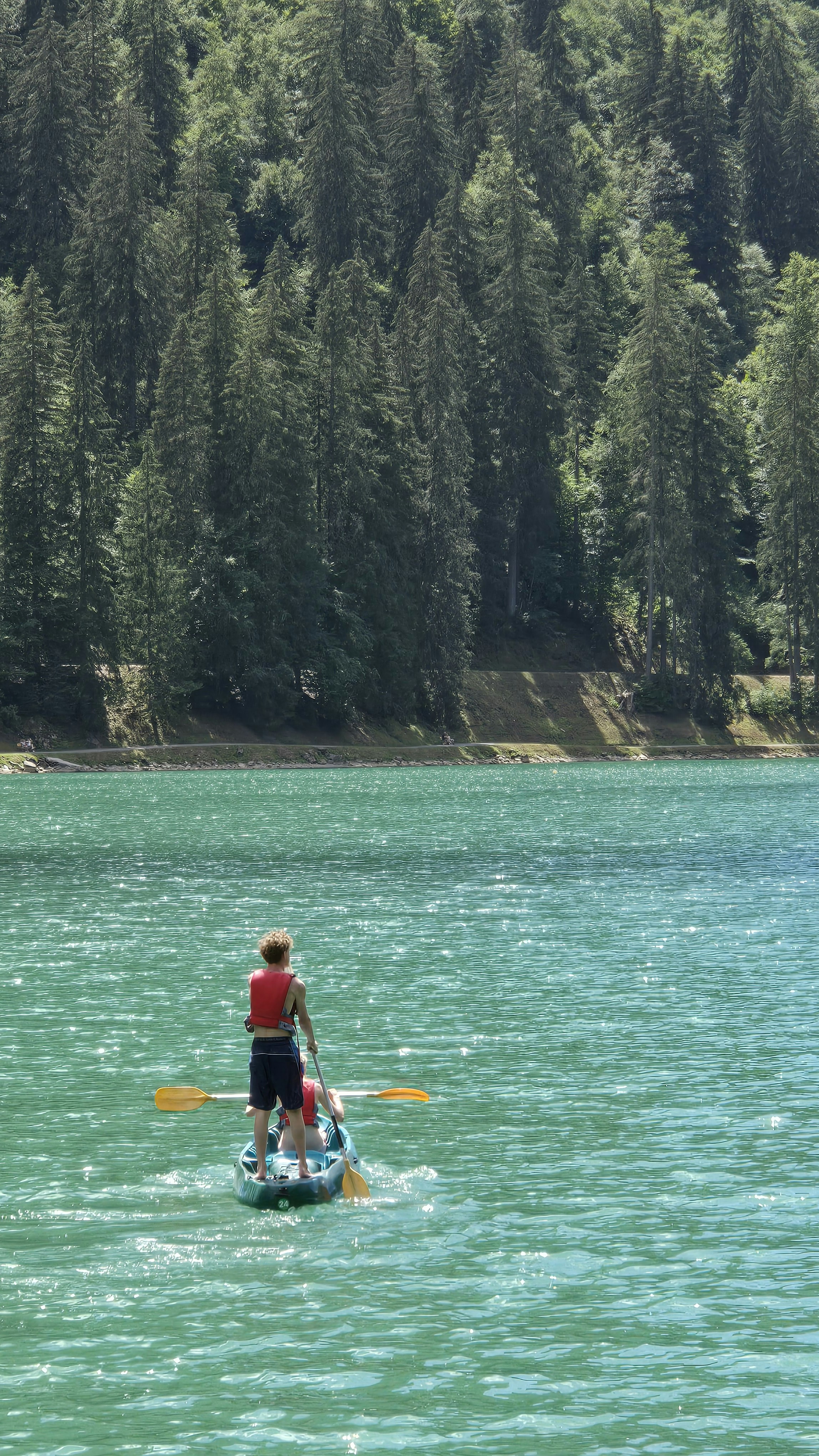 Two-Person Paddle on Mirror-Blue Lake Against Forest Backdrop