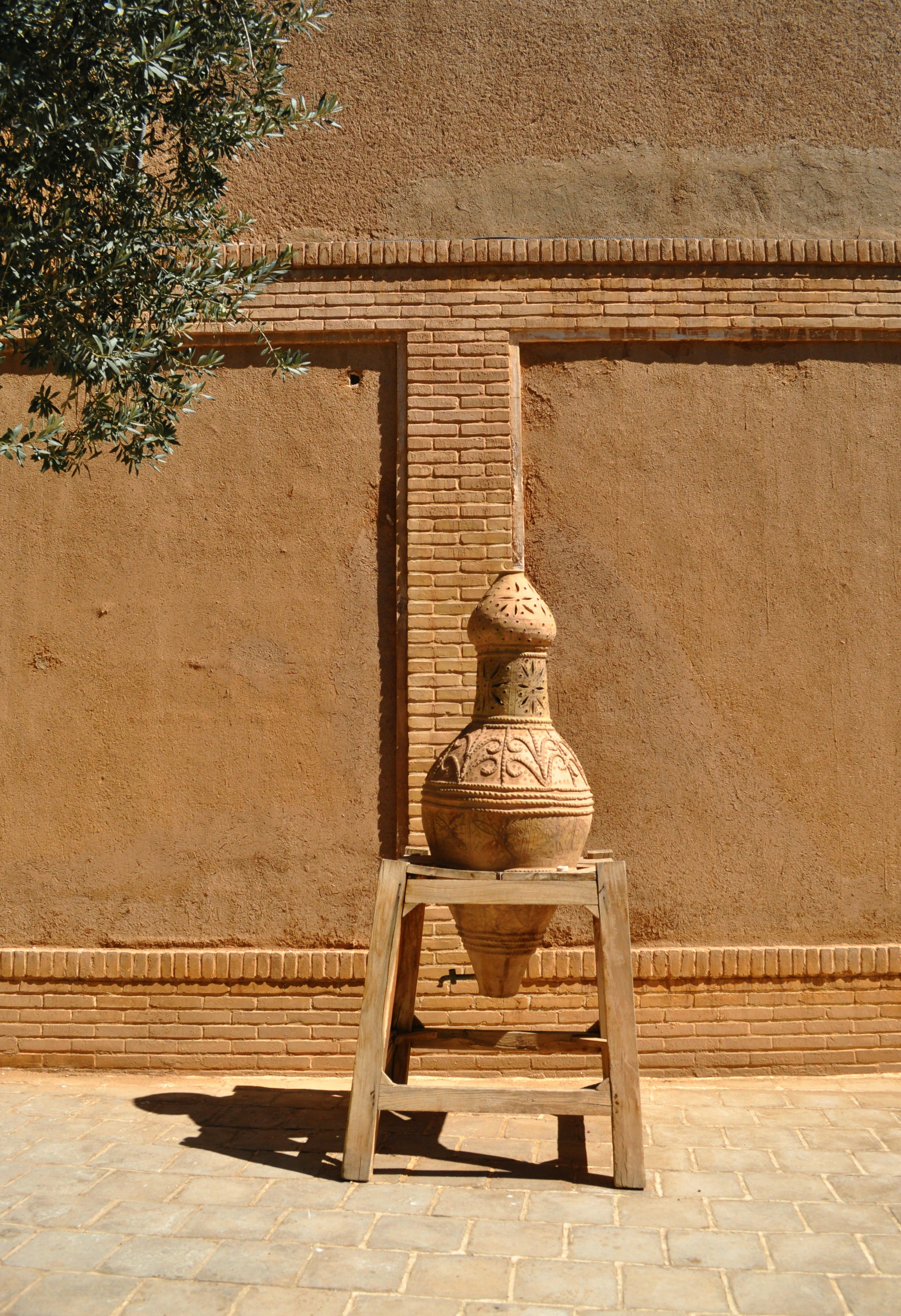 Desert Vessel on a Rustic Stool Under Sunlit Brick Wall