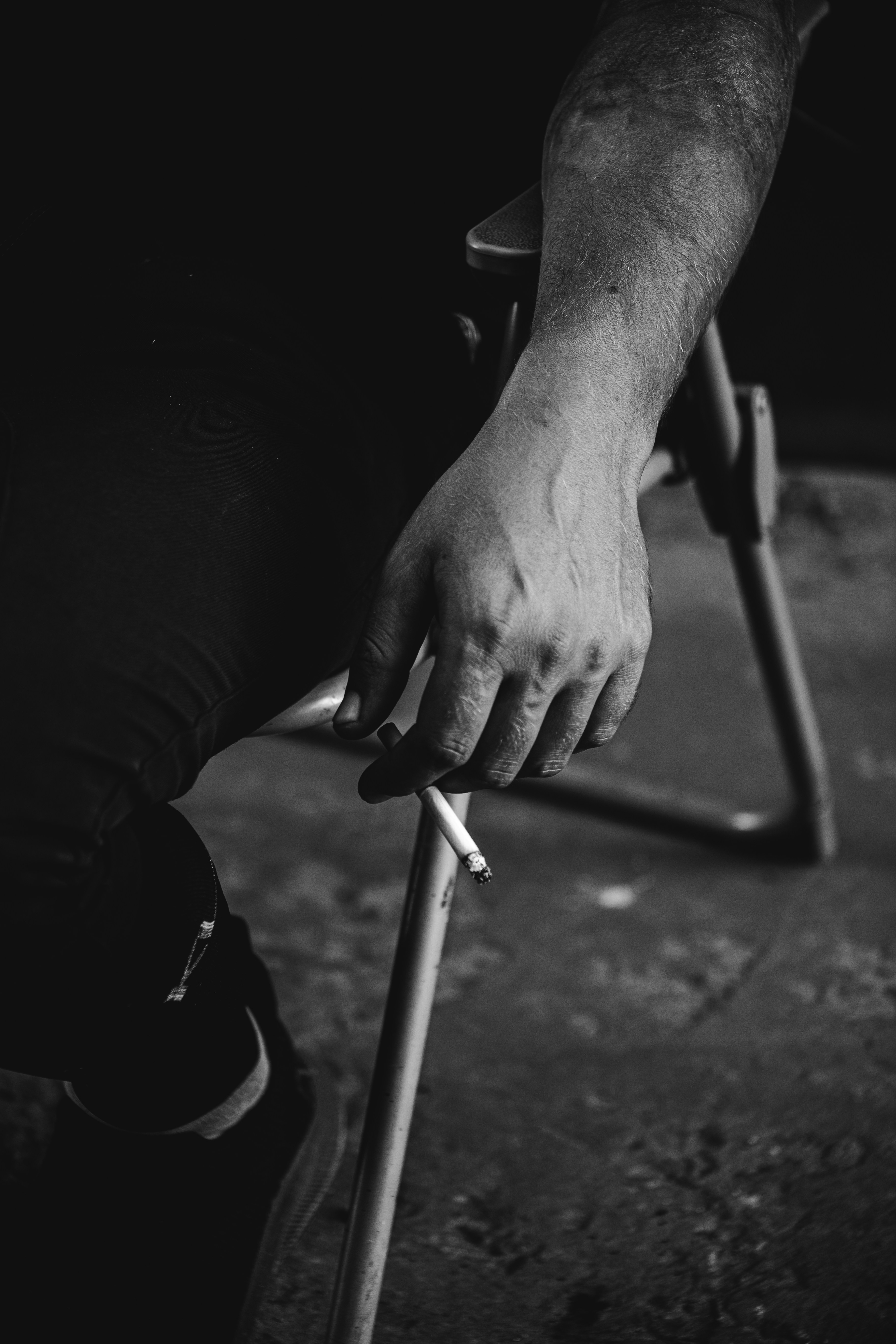 Grim Grip: A Cigarette Between Bare Fingers and a Folded Chair