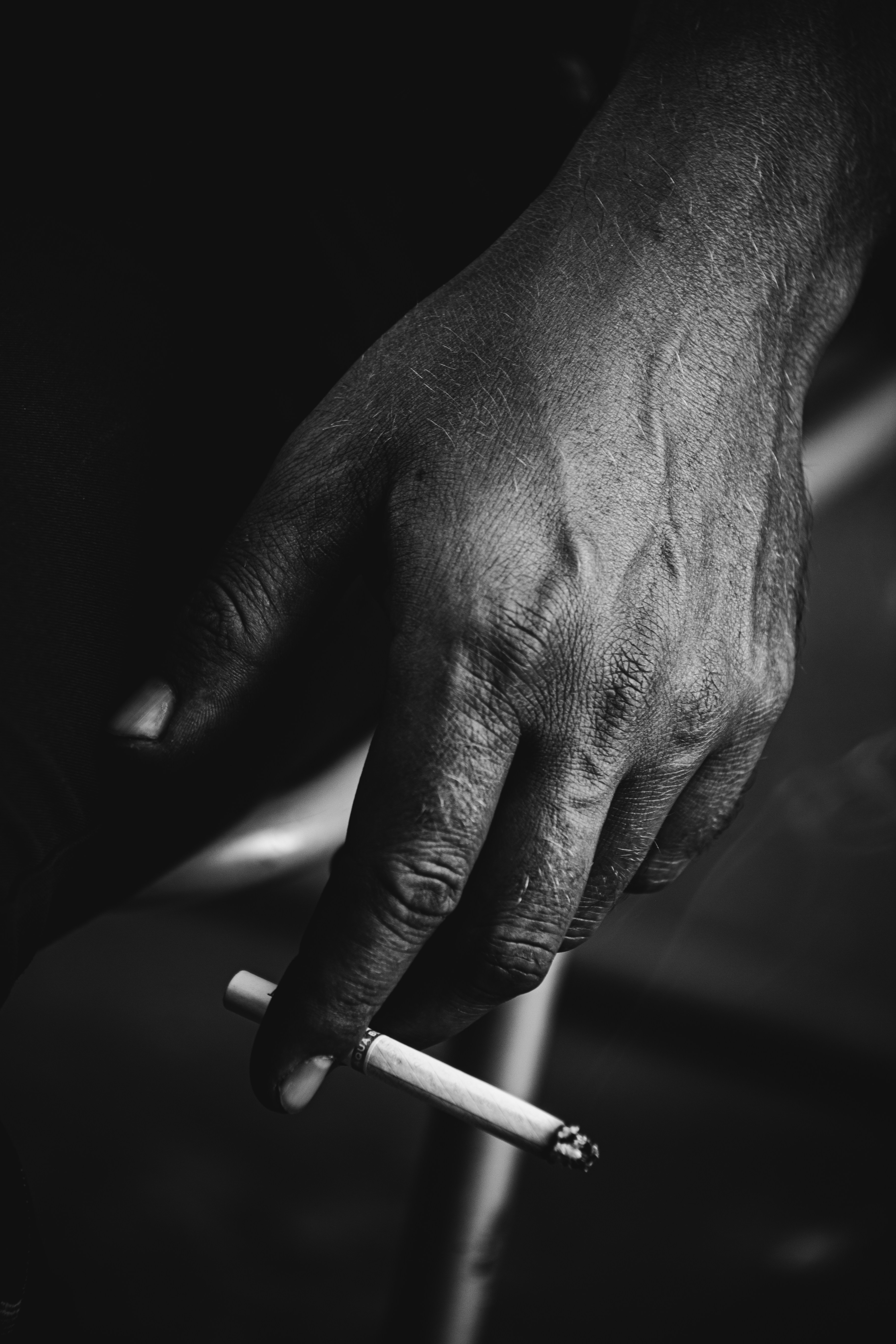 Ashen Grasp: A Cigarette Between Rough Hands in monochrome
