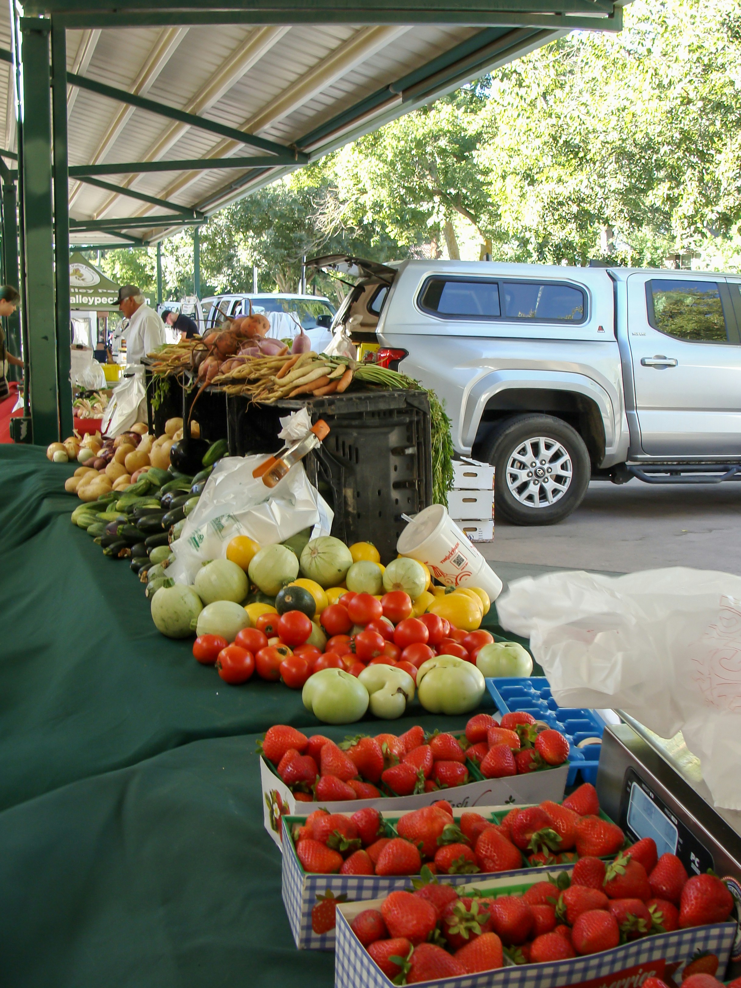 Market Stand at Dusk: Car, Produce, and Activity Collide