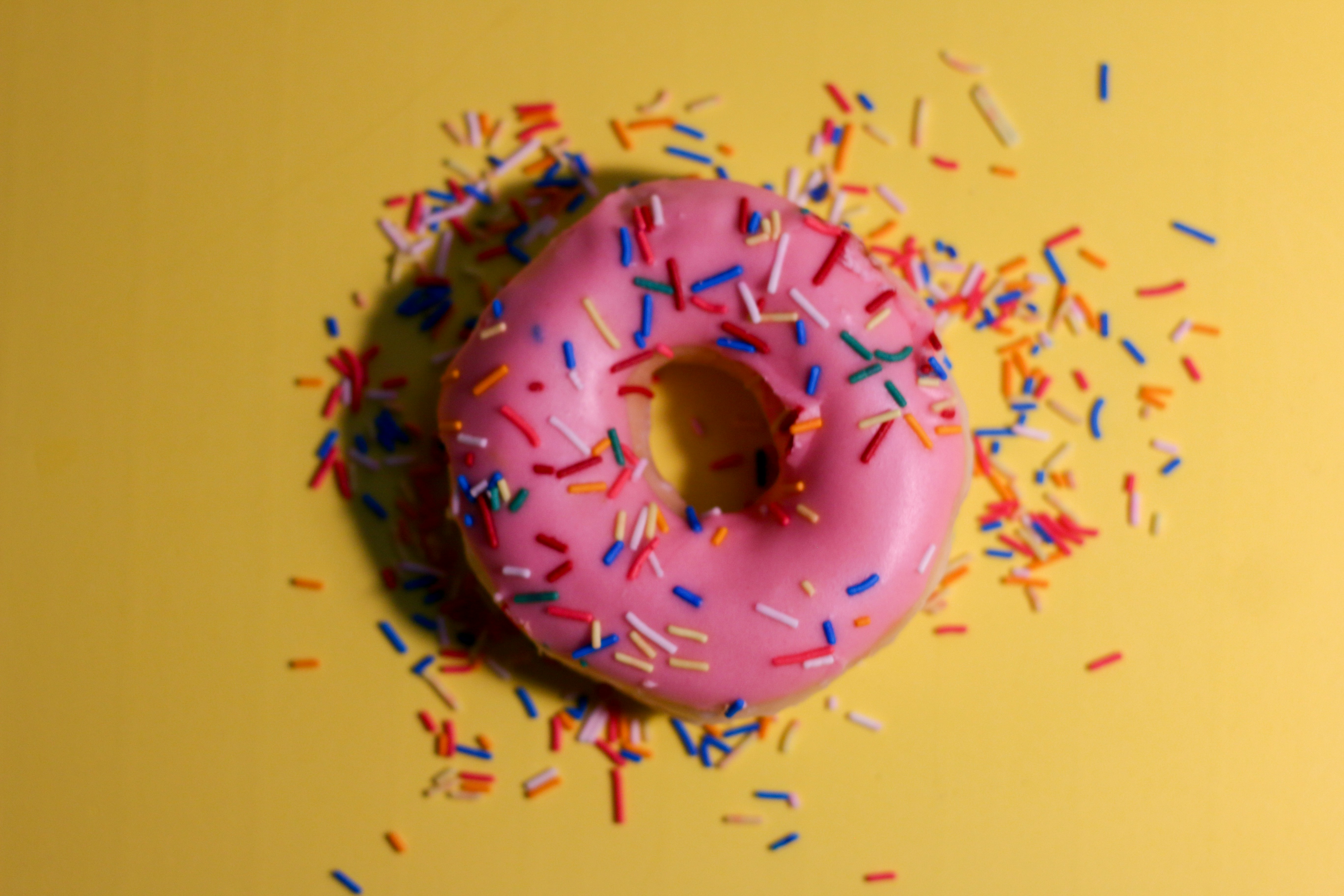Sprinkled Sweetness: A Pink Donut on a Sunny Canvas