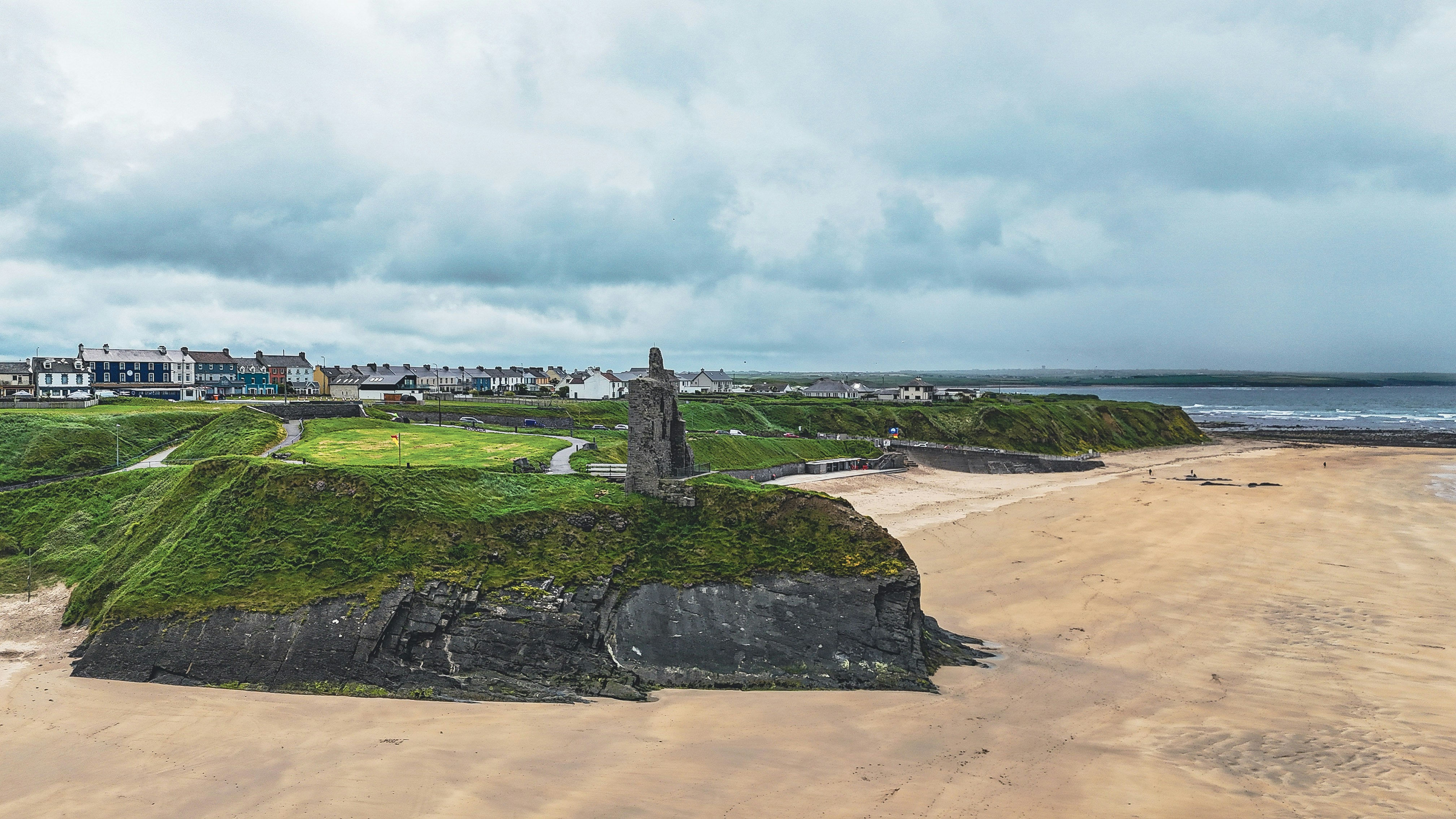 Coastal Ruin Overlook: Grass, Cliff, and Sea on a Windy Day