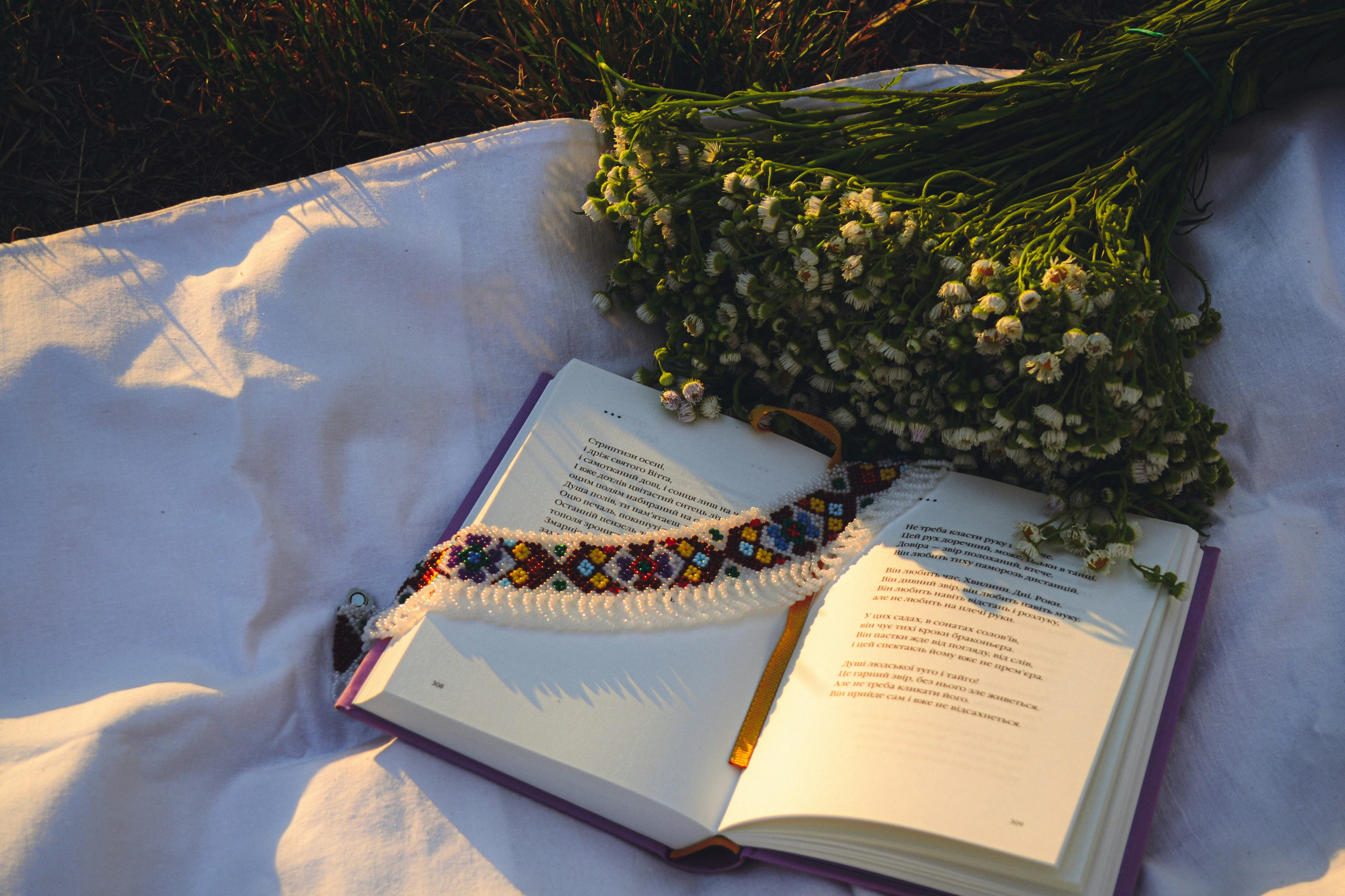 Quiet Reading Under Floral Light: Open Pages and White Blanket