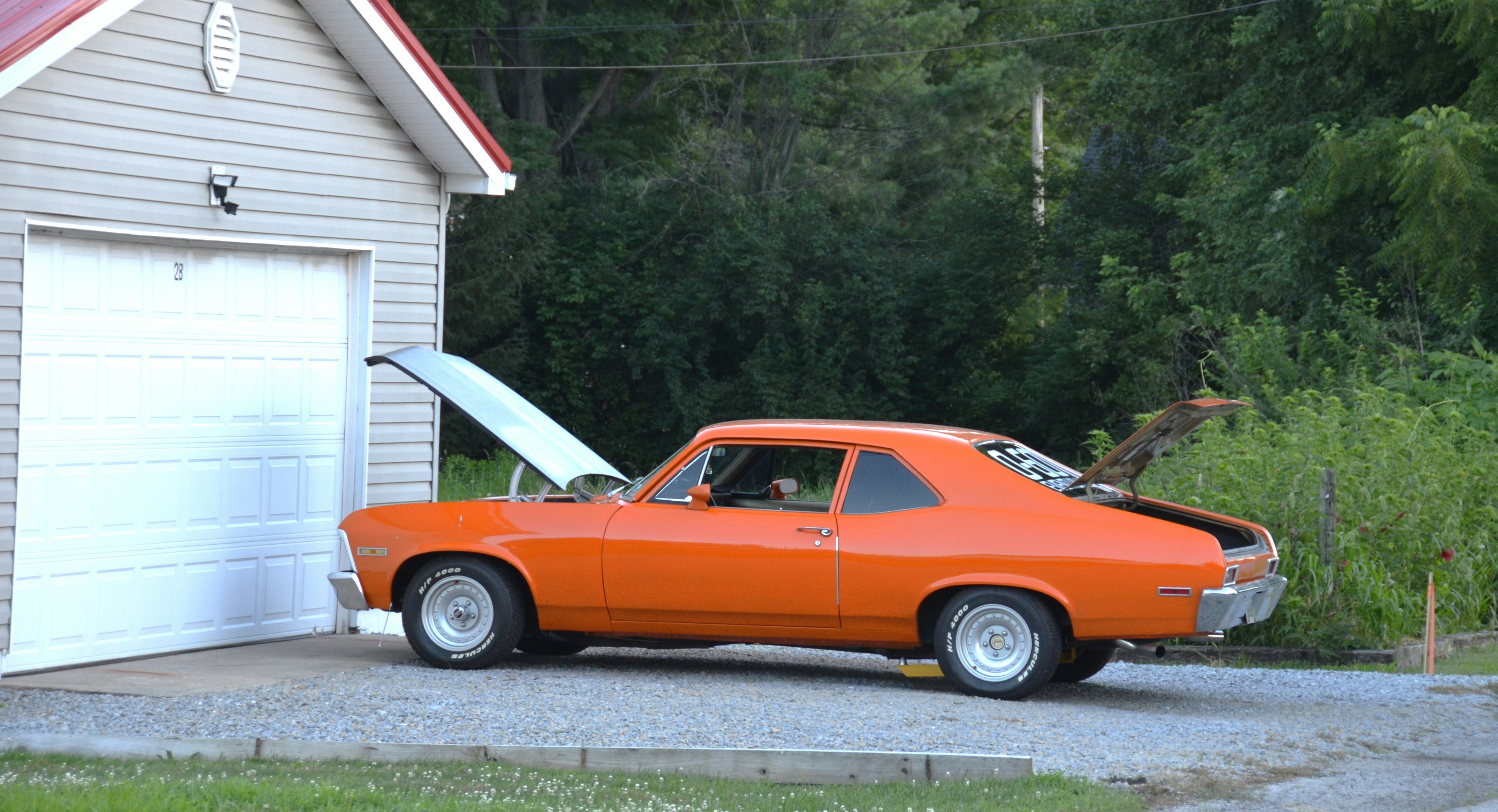 Orange Classic in Front of a Garage with Open Hoods