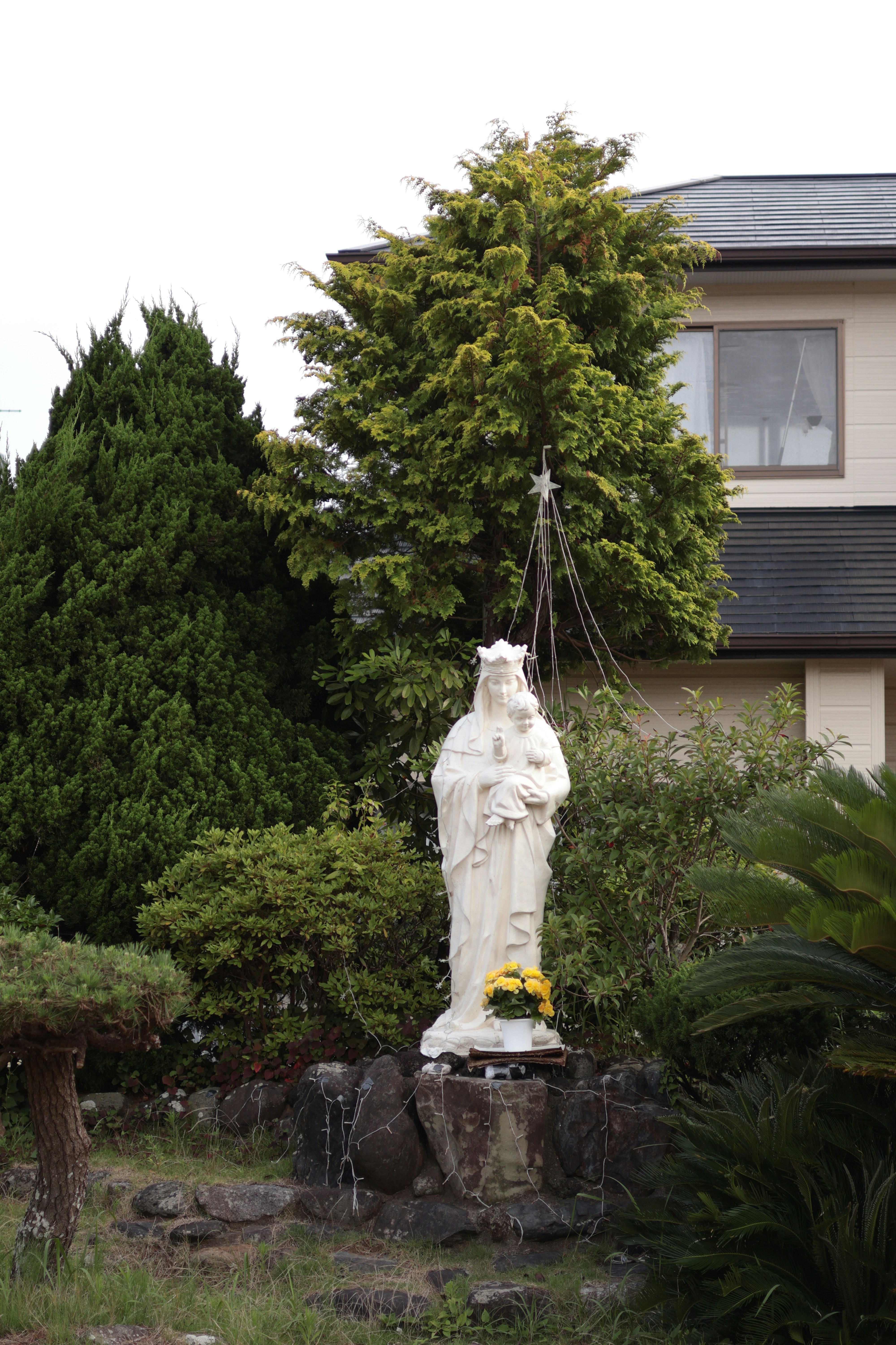 Statue on a rock fountain under a tree in a suburban garden