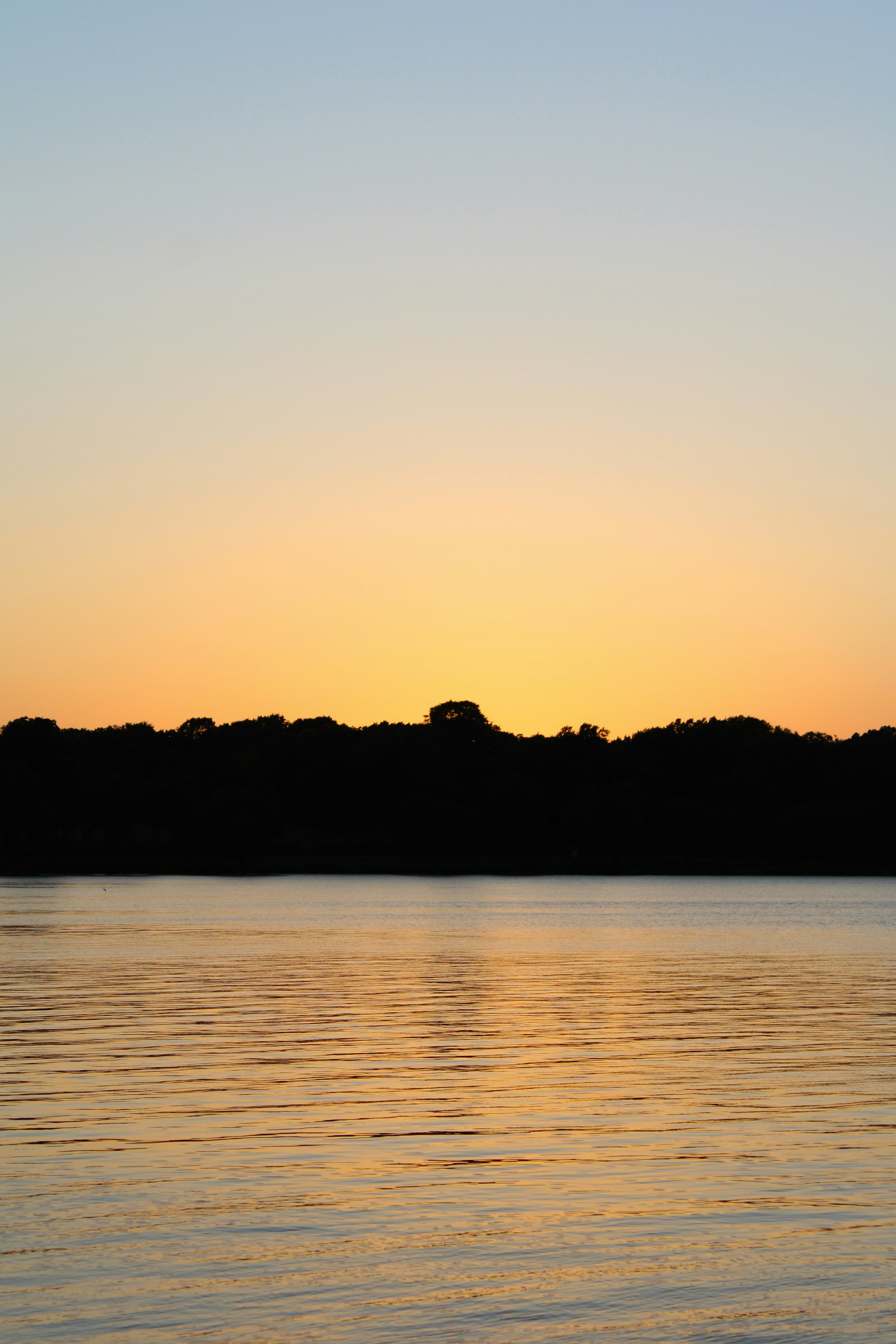 Silhouette at Dusk: A Quiet Horizon over Calm Waters