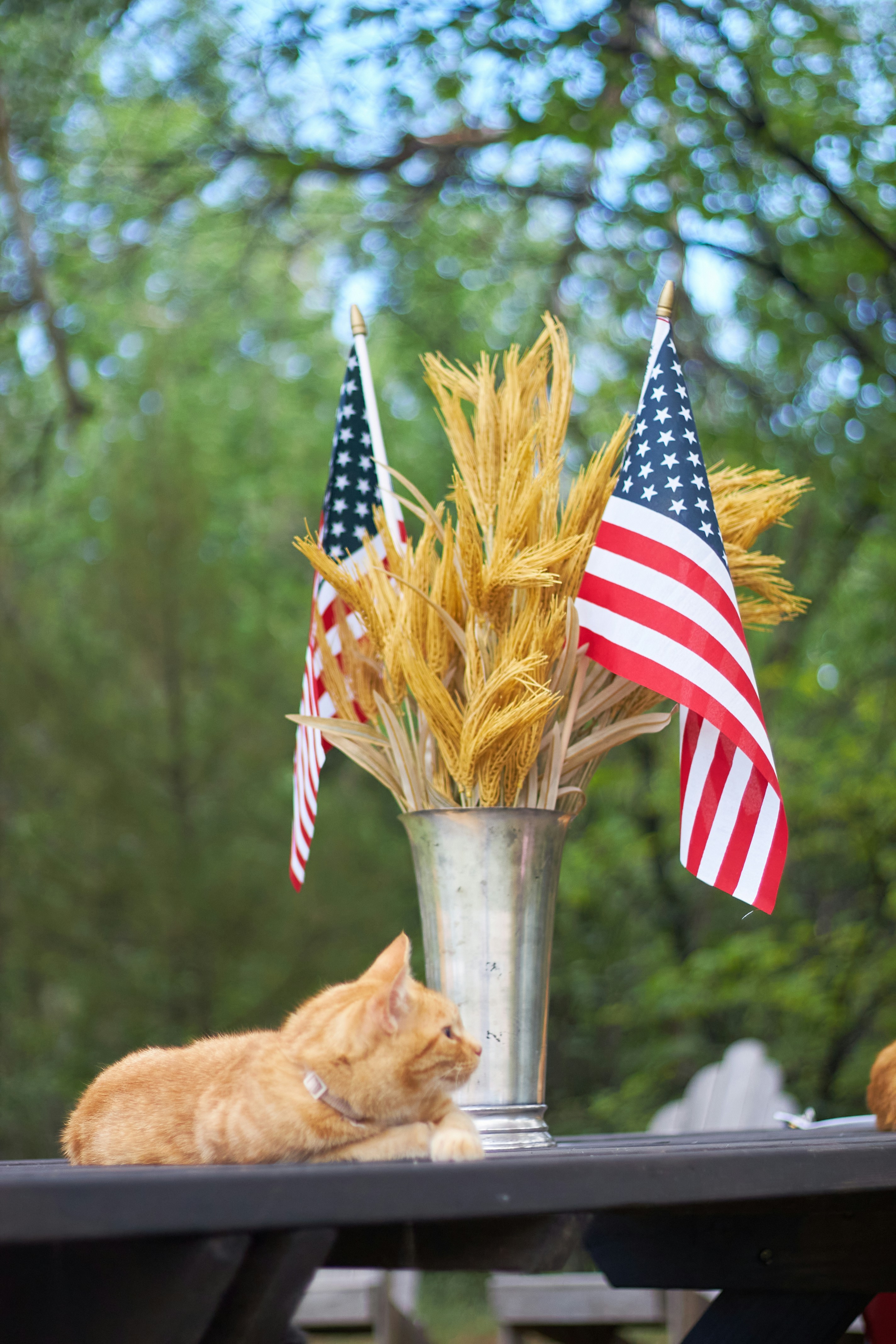 Patriotic vignette: flags flanking a simple bouquet atop a weathered pedestal
