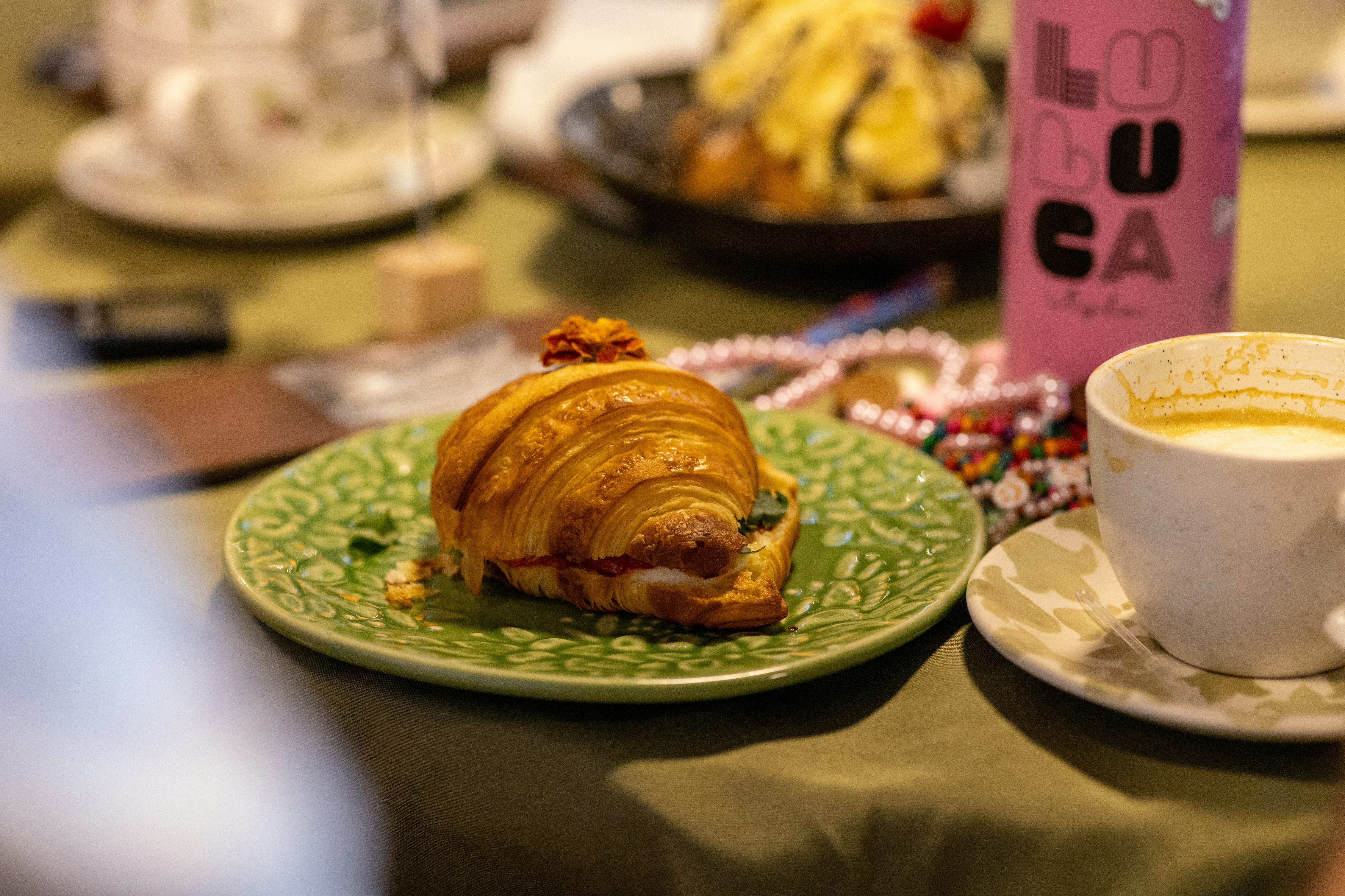 Crescent pastry centerpiece on a green plate with a coffee cup