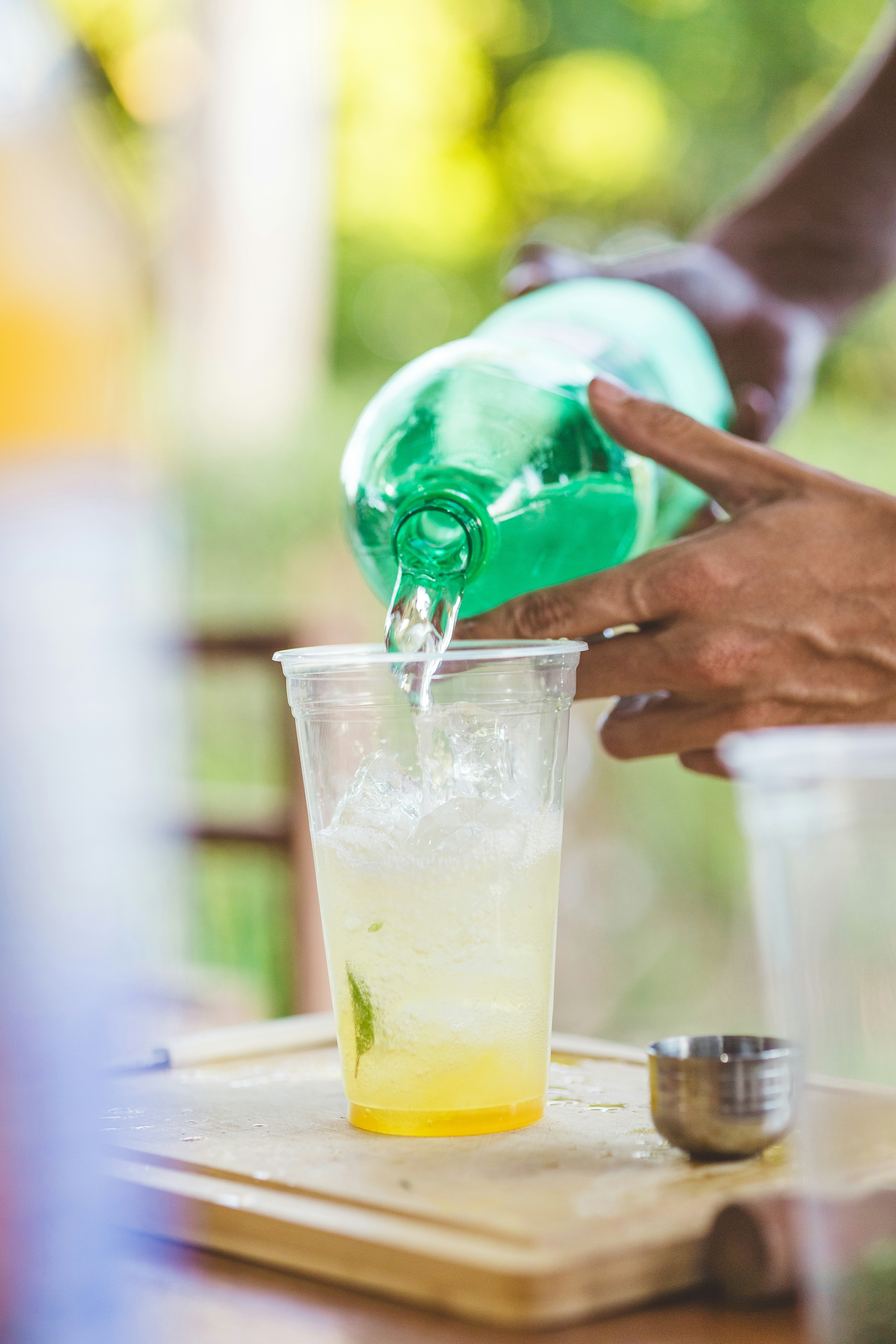 Green Bottle Pour into a Transparent Cup on a Wood Surface