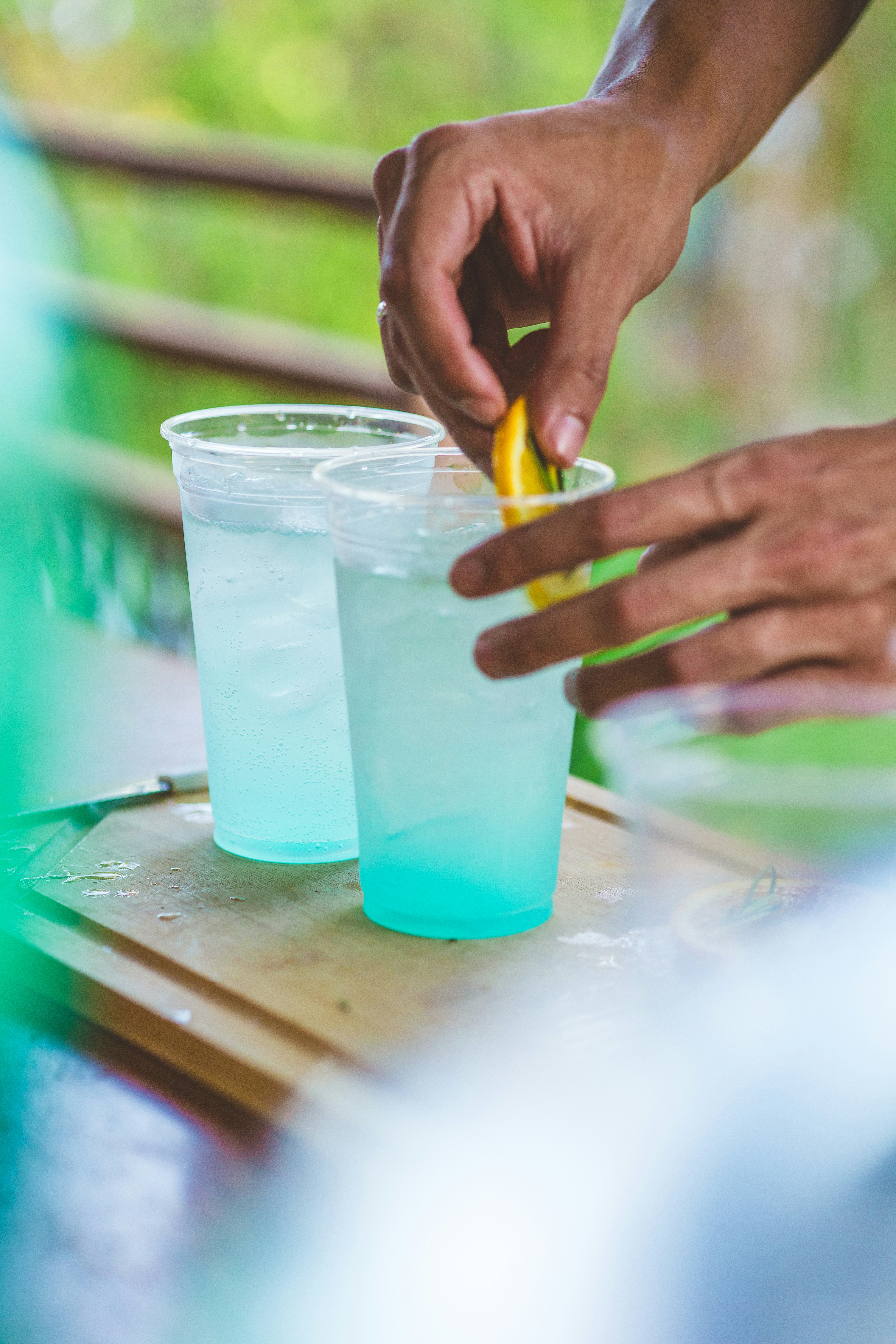 Citrus Splash: hands preparing turquoise drinks on a sunlit deck