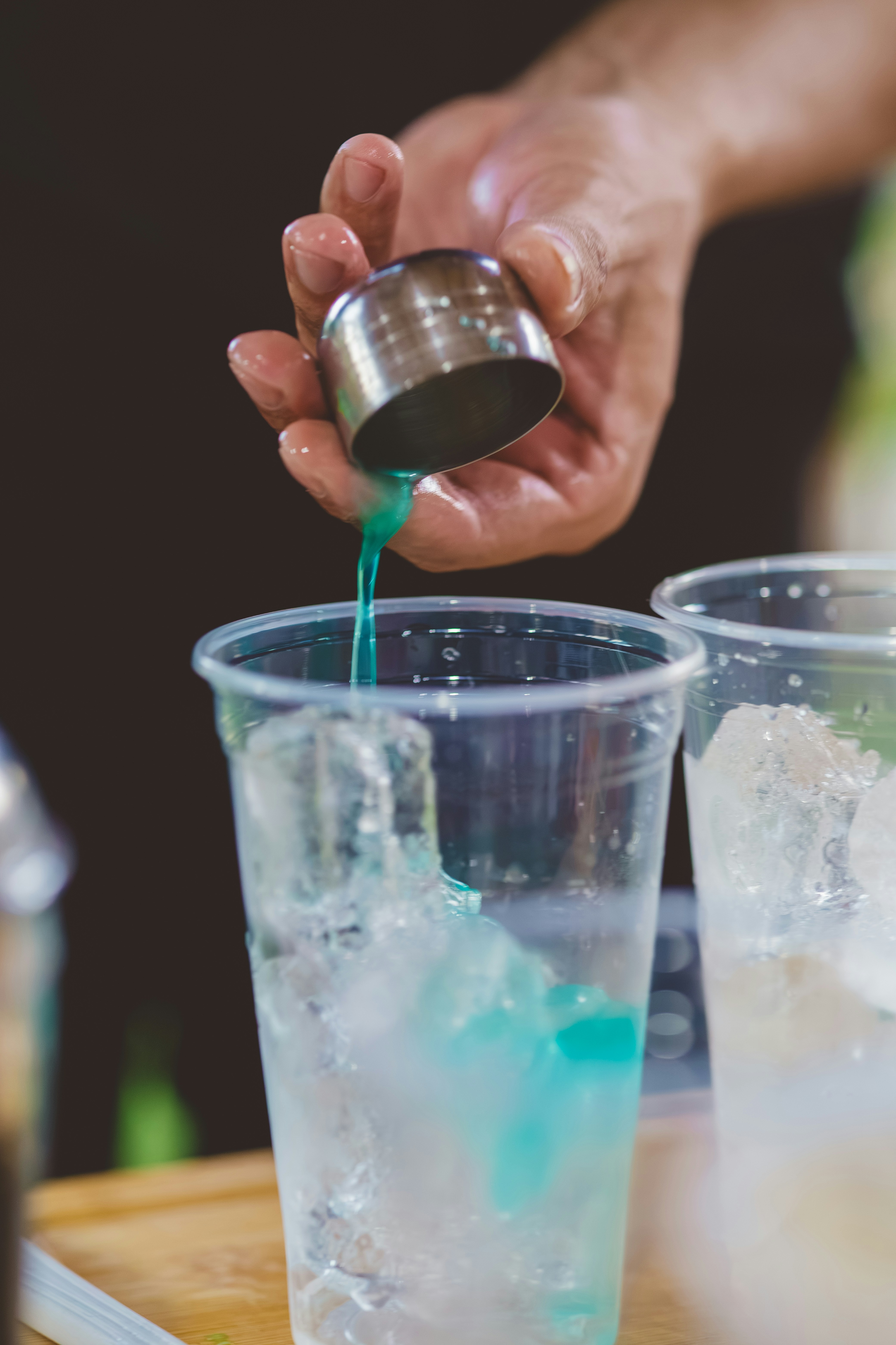 Pouring turquoise elixir: a close-up of a hand creating vivid ice-cold art