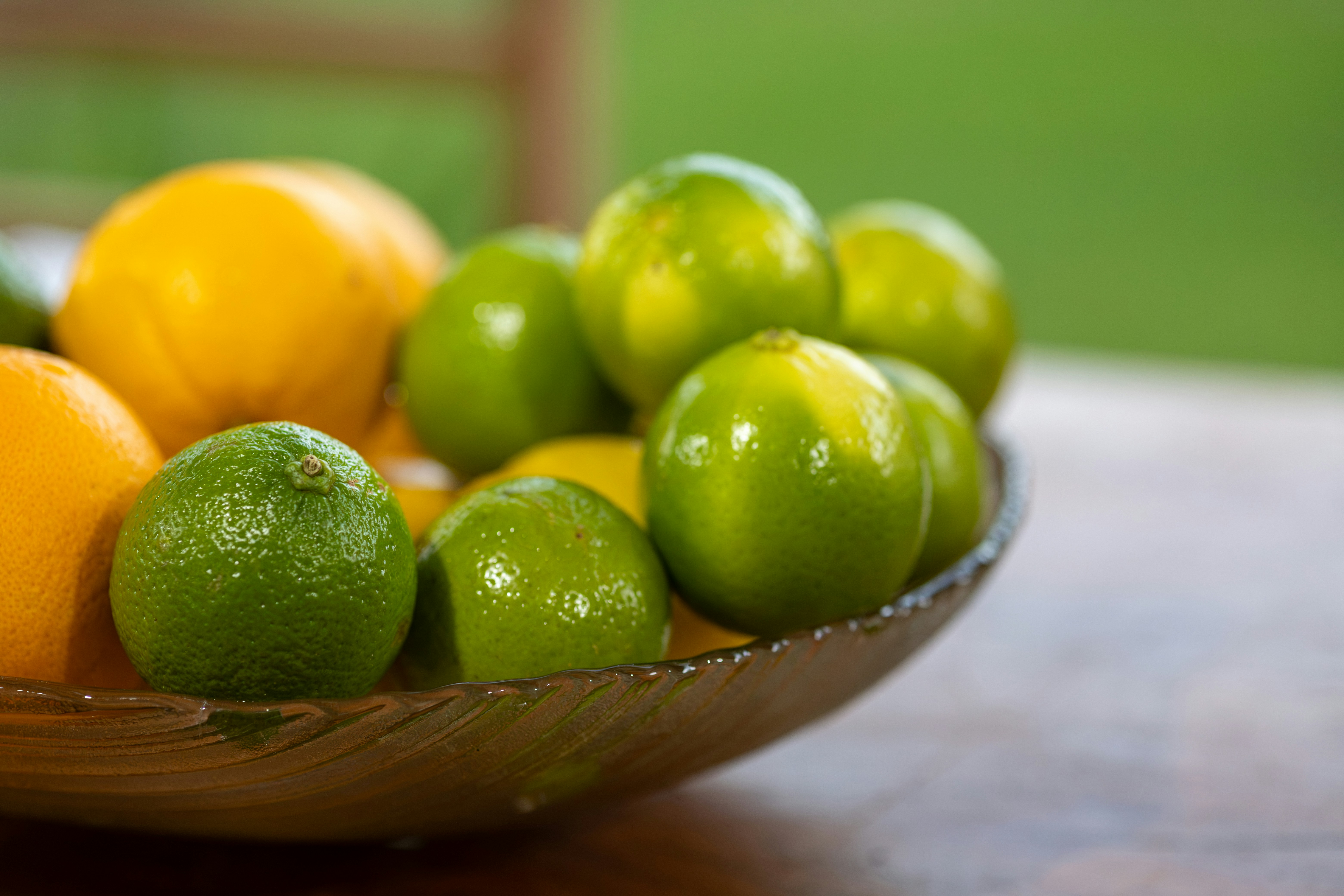 Citrus Balance: A Bowl of Limes and Oranges on a Wooden Table