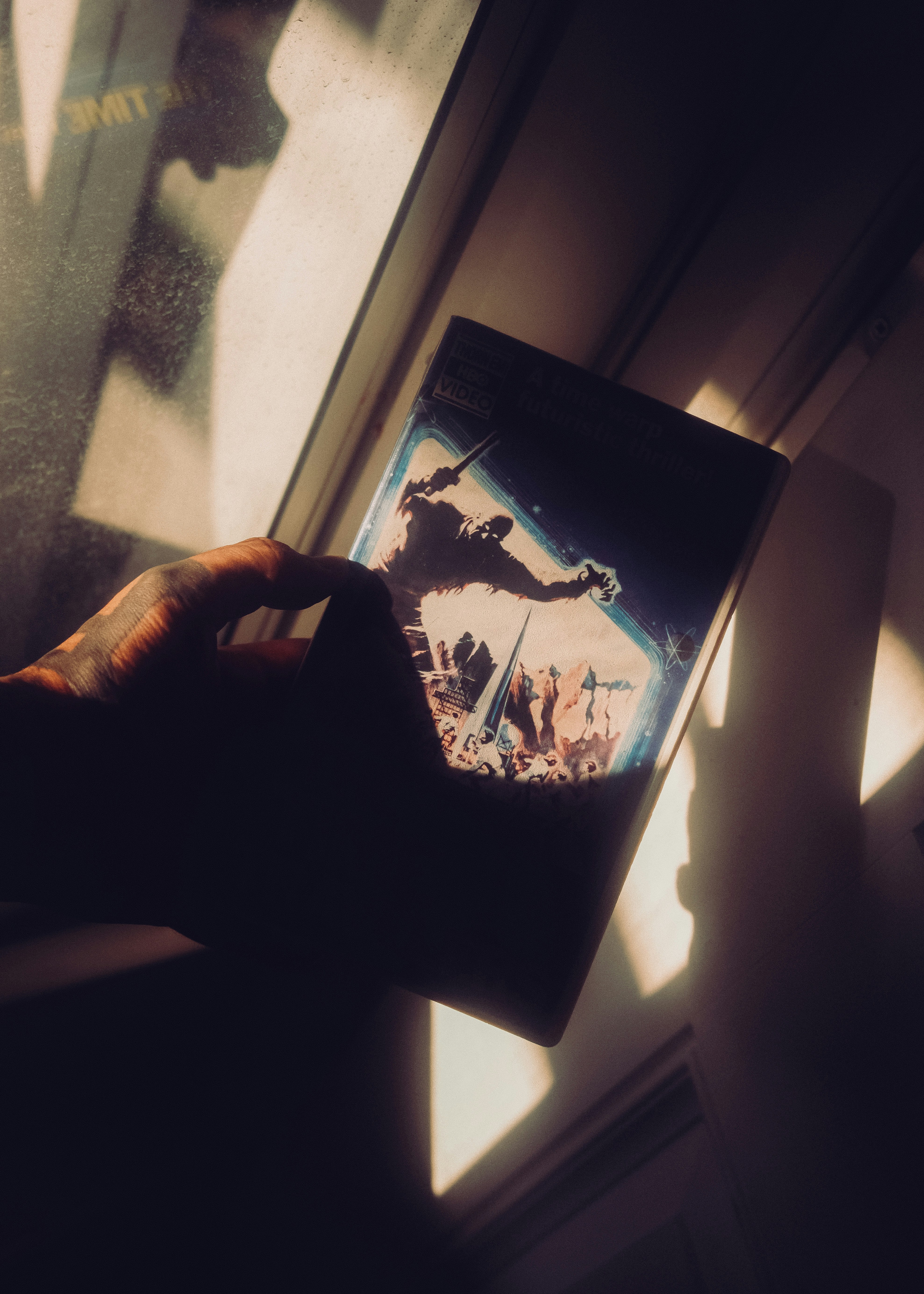 Shadowed Hands and a Retro Screen: A Quiet Moment with a Movie Poster Folded in Light