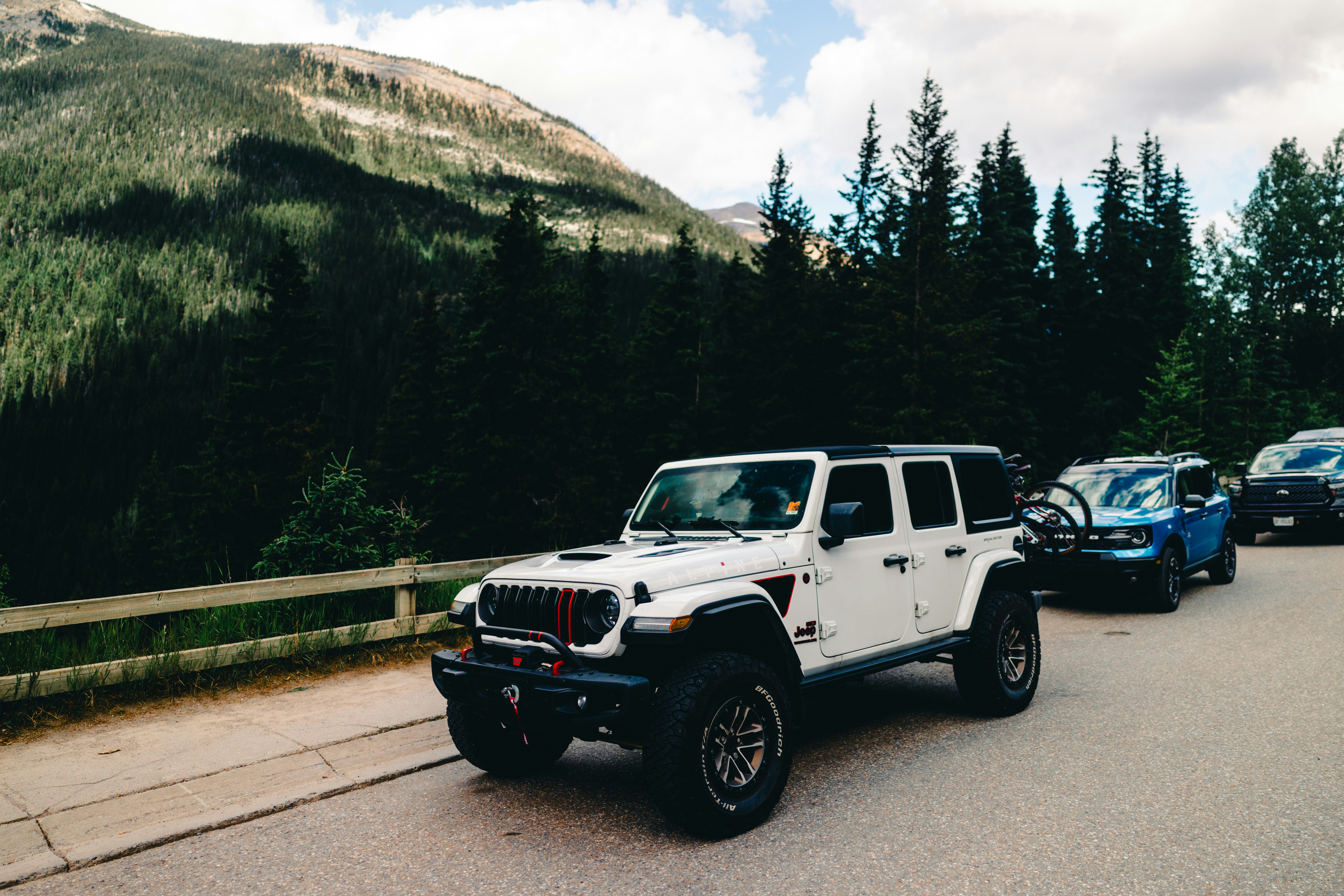 Line of Steel and Sky: White Jeep Leads the Mountain Road