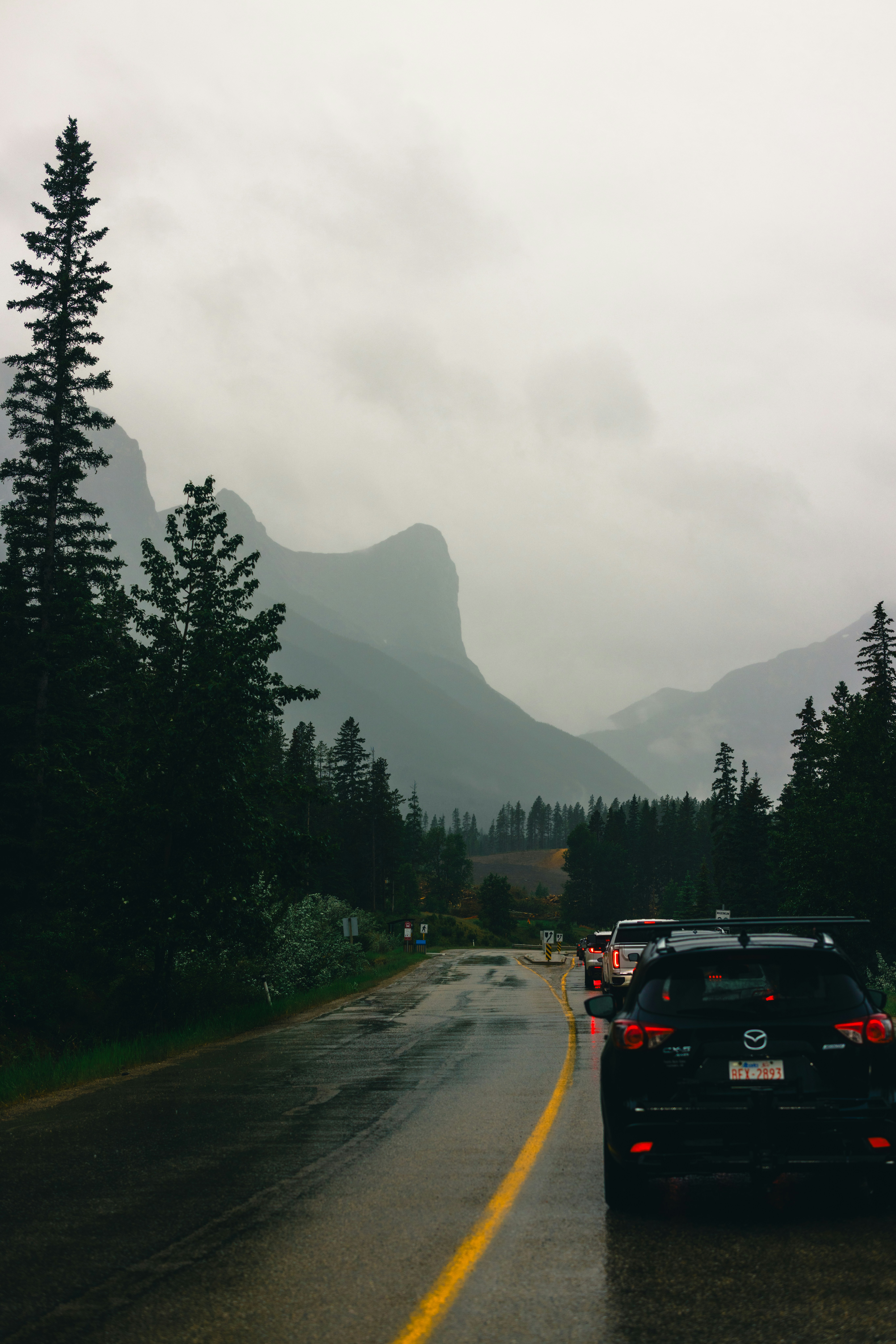 Converging Rain-Slicked Highway toward Misty Peaks