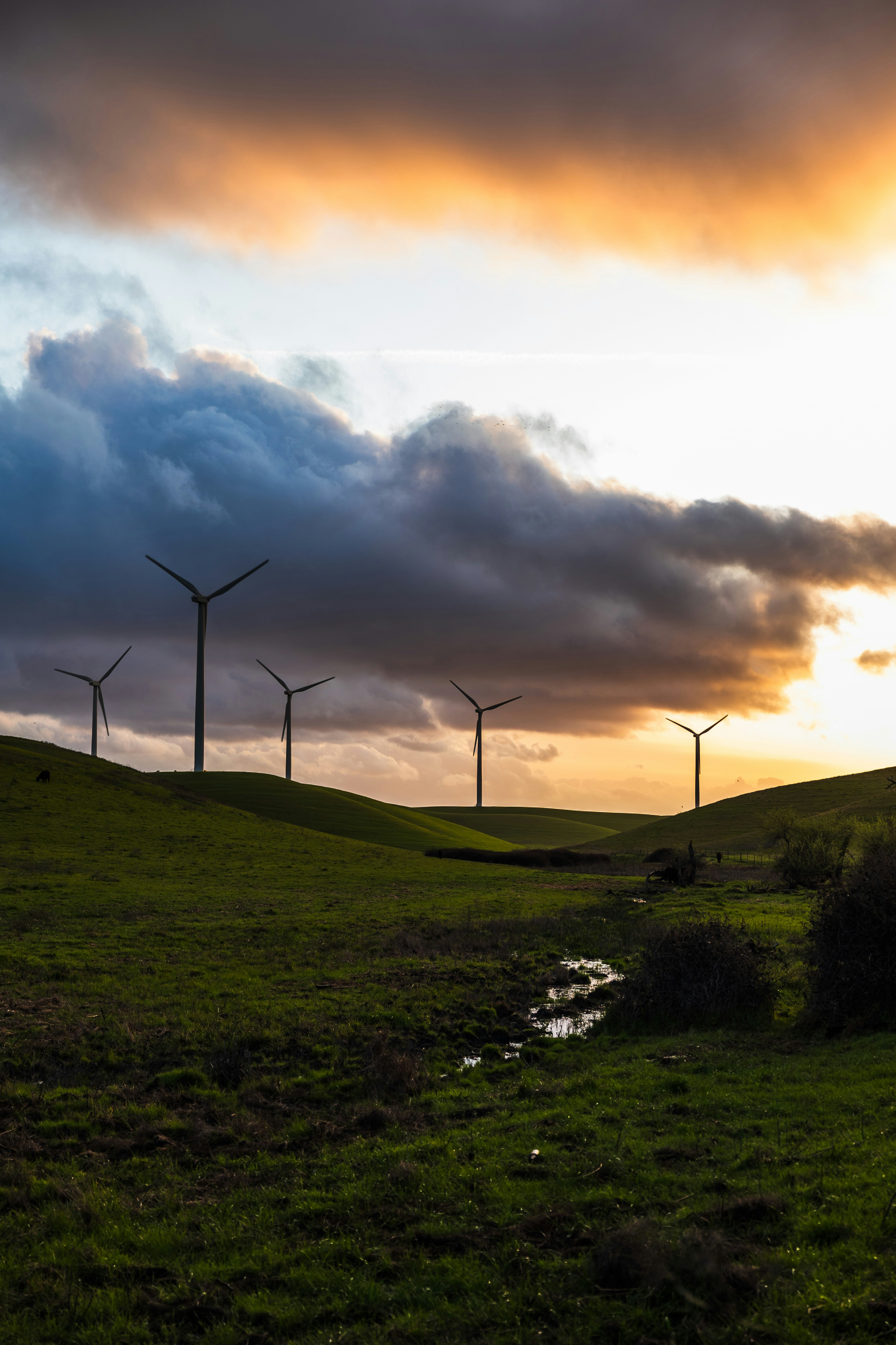 Windmills at Dusk: A Quiet Valley Under Firelit Clouds