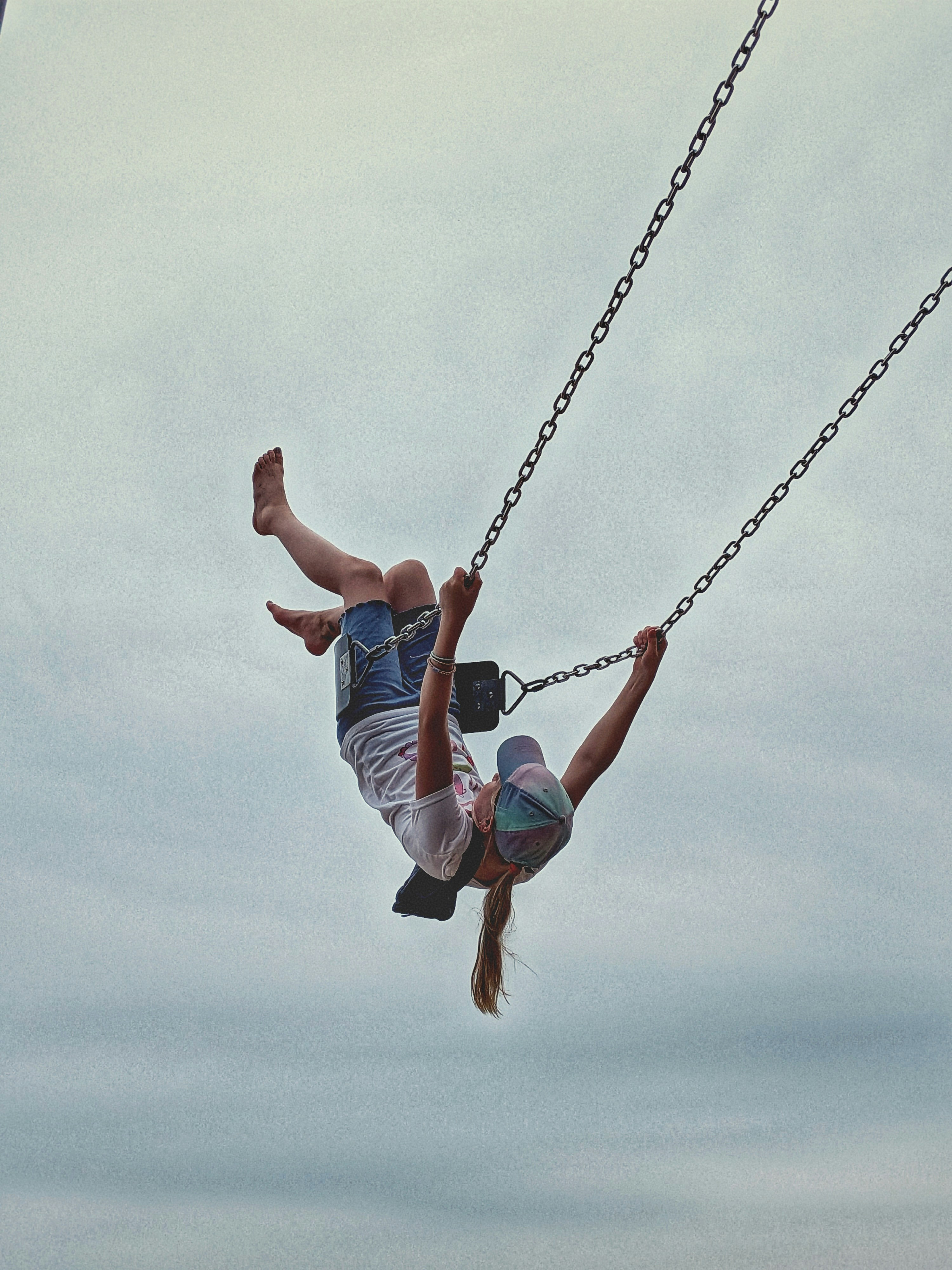 Suspended Joy: A Swinging Portrait Against a Quiet Sky
