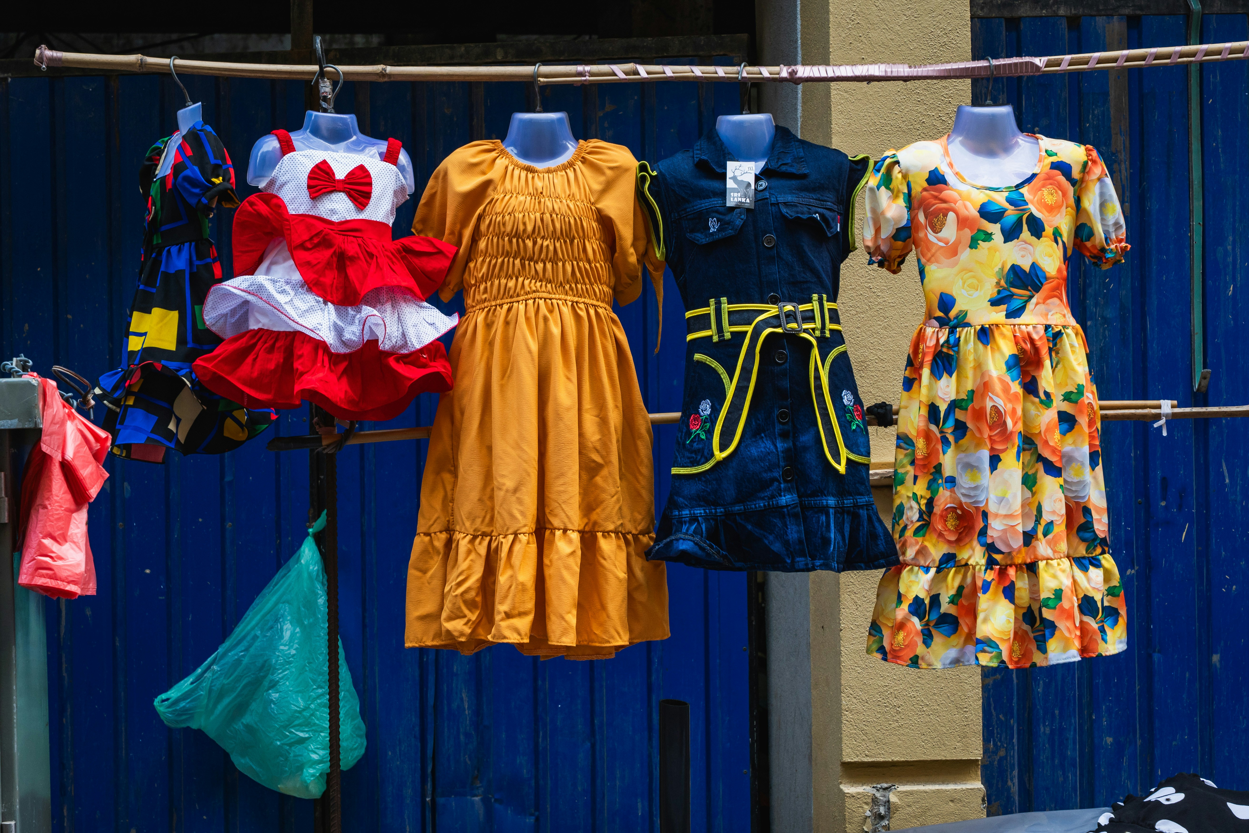 Vivid garments on a sunlit clothesline against a weathered blue fence