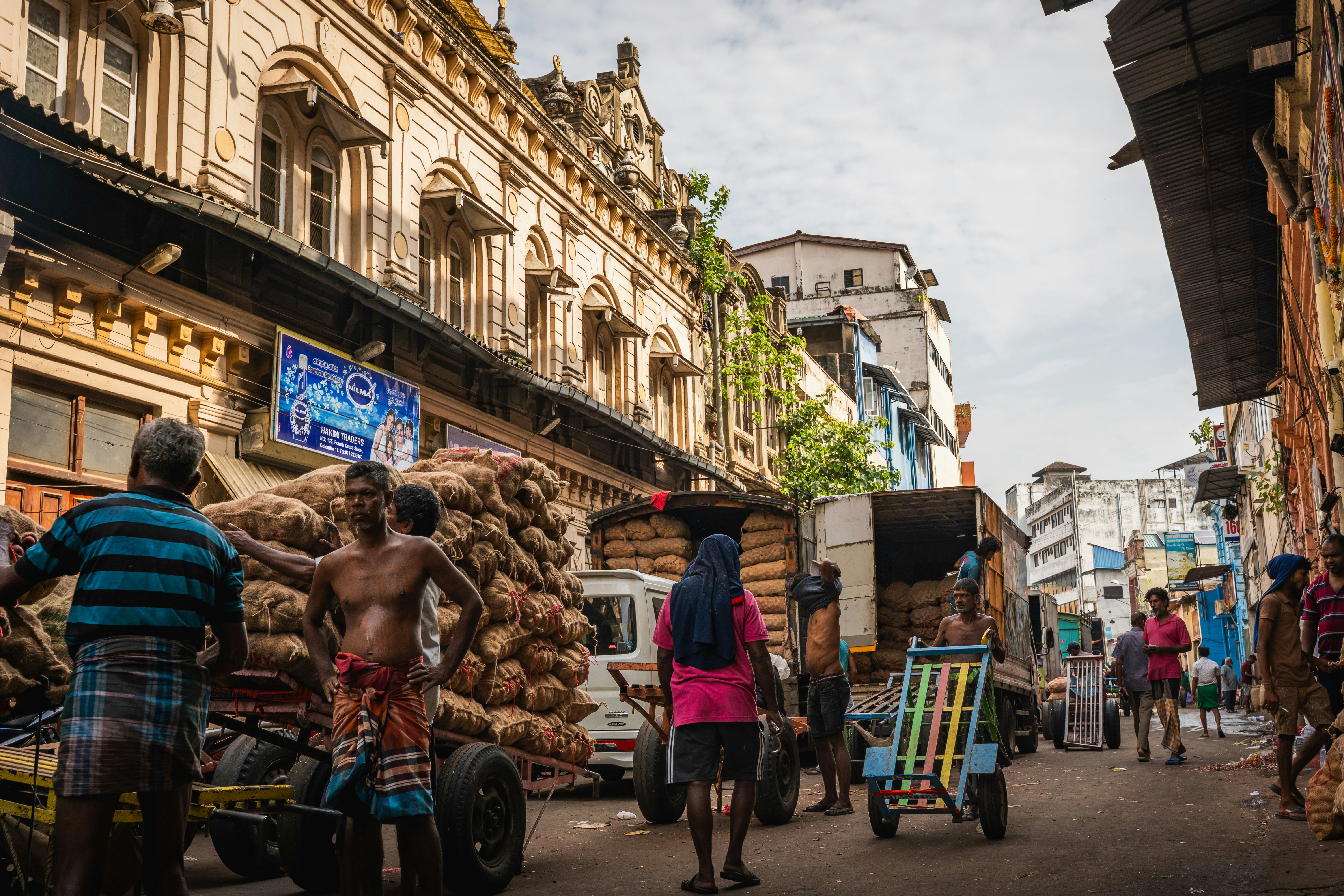 City Street Ledger: Traders, Carts, and a Looming Haystack Parade