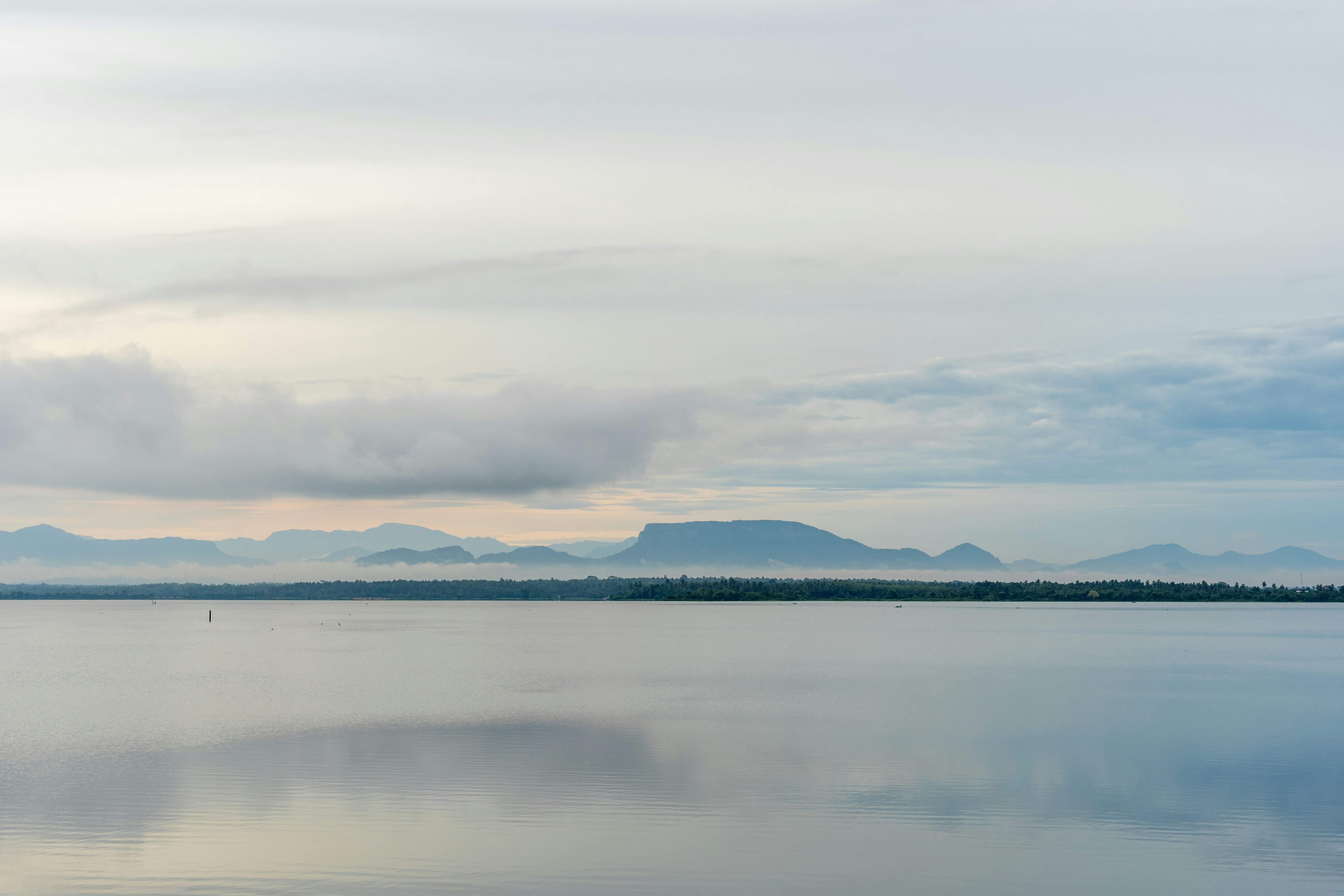 Silenced Horizon: Calm Lake with Distant Blue Escarpments at Dusk