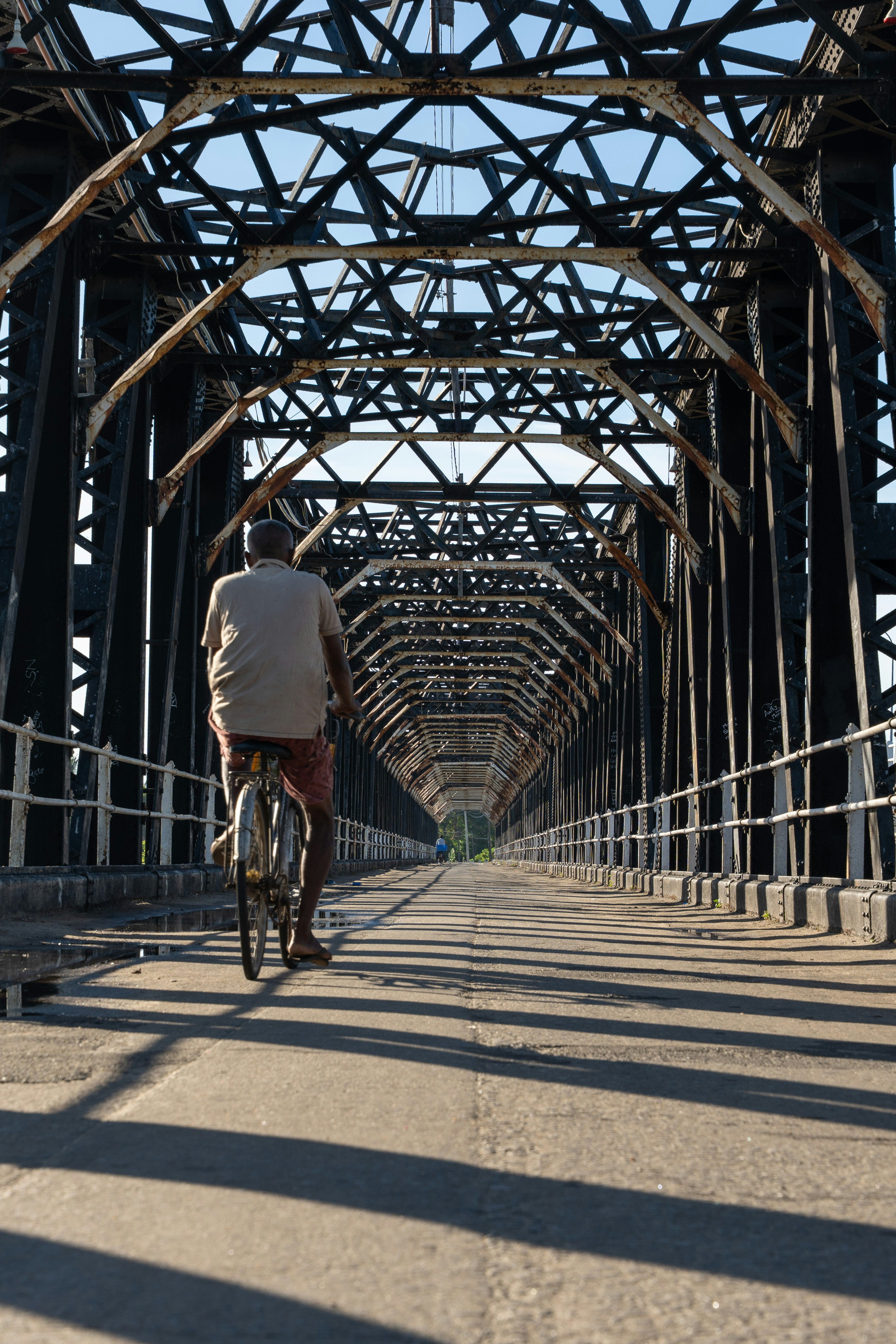 Pedal through the Grid: A lone cyclist on a rusting steel bridge