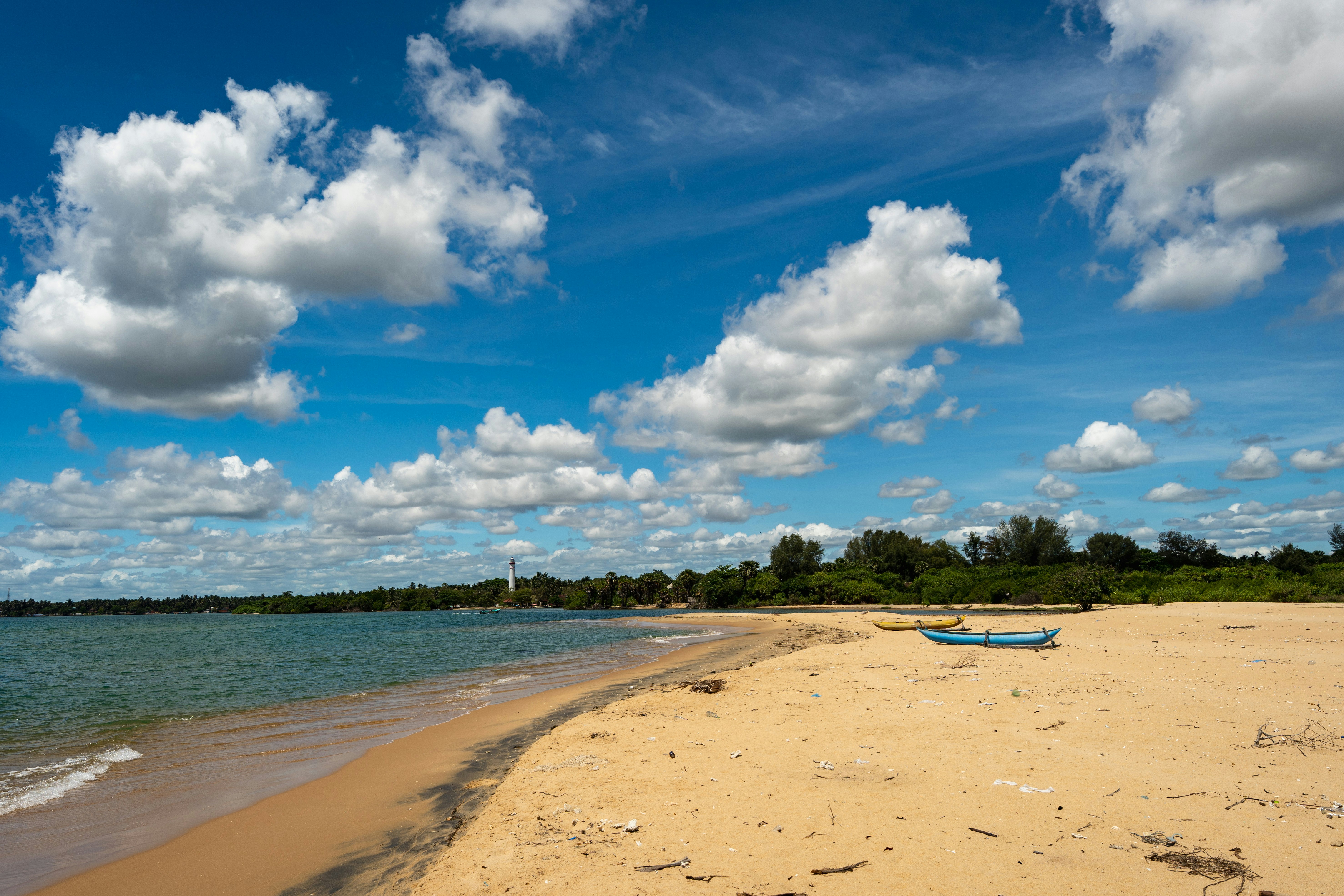 Dusty shoreline with blue rowboat under a sky of fluffy clouds