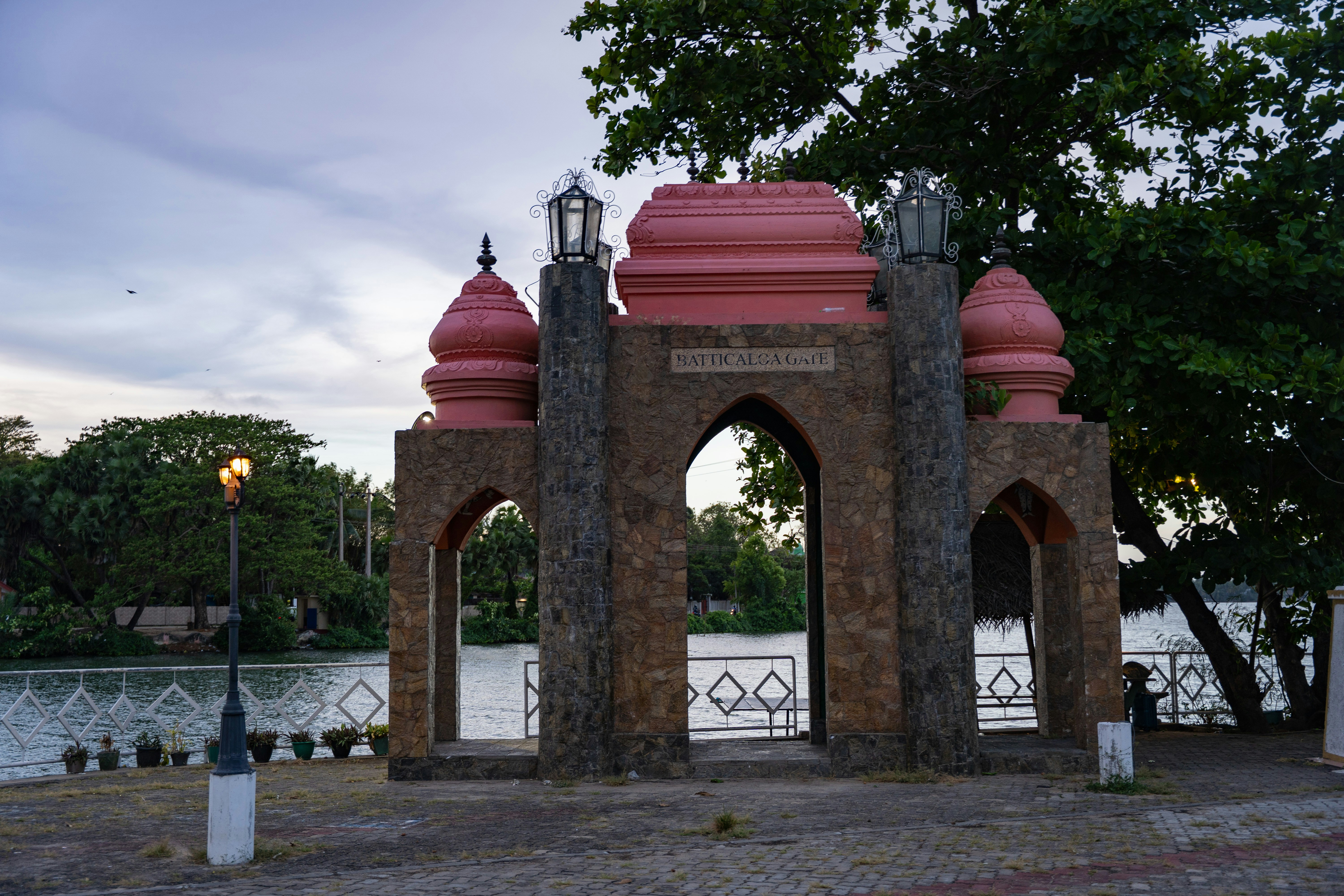 Sunlit Gateway: A Colonial Arch Framed by Towering Trees